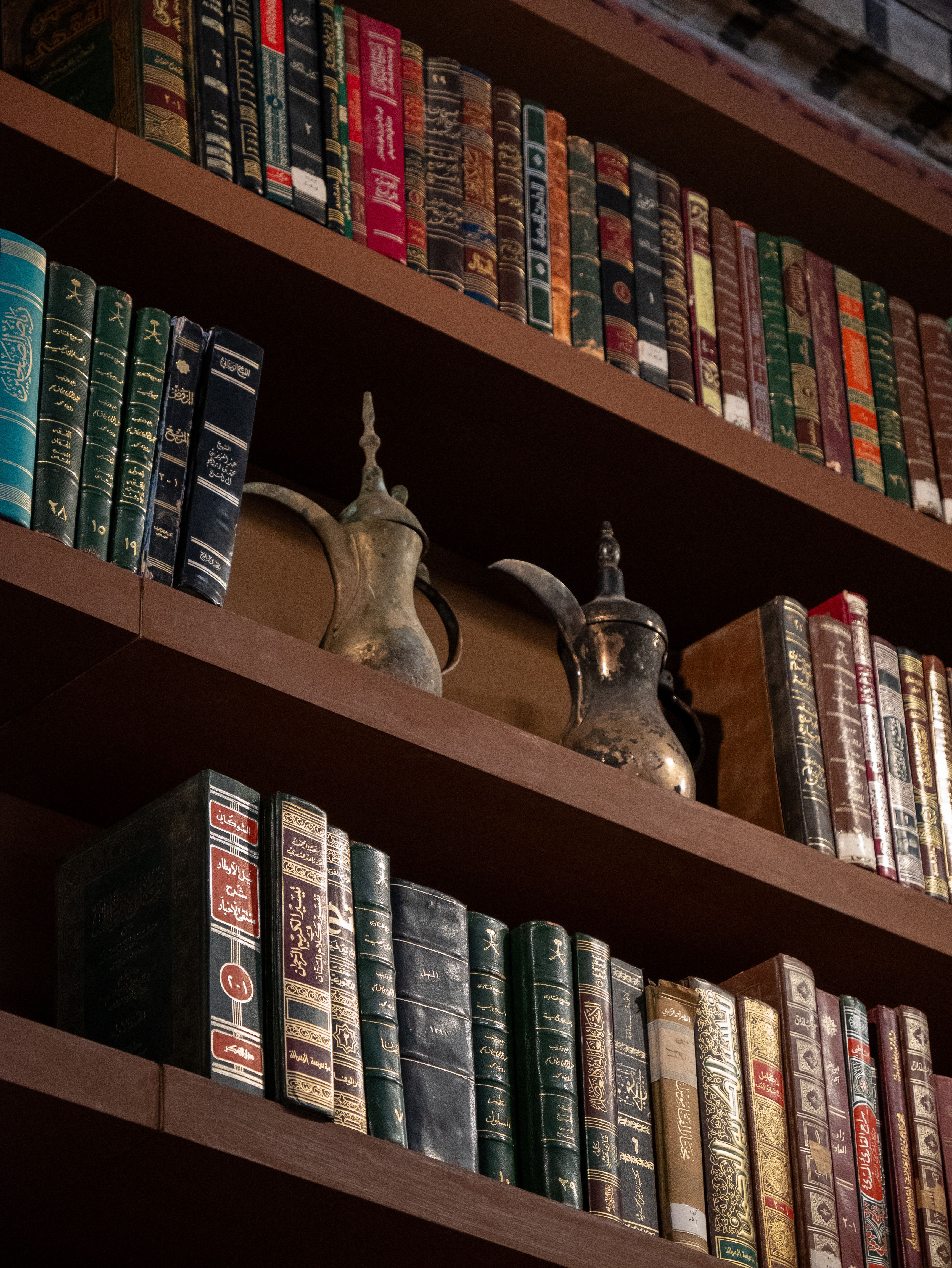 Books on wooden bookshelf with ornate teapots · Free Stock Photo