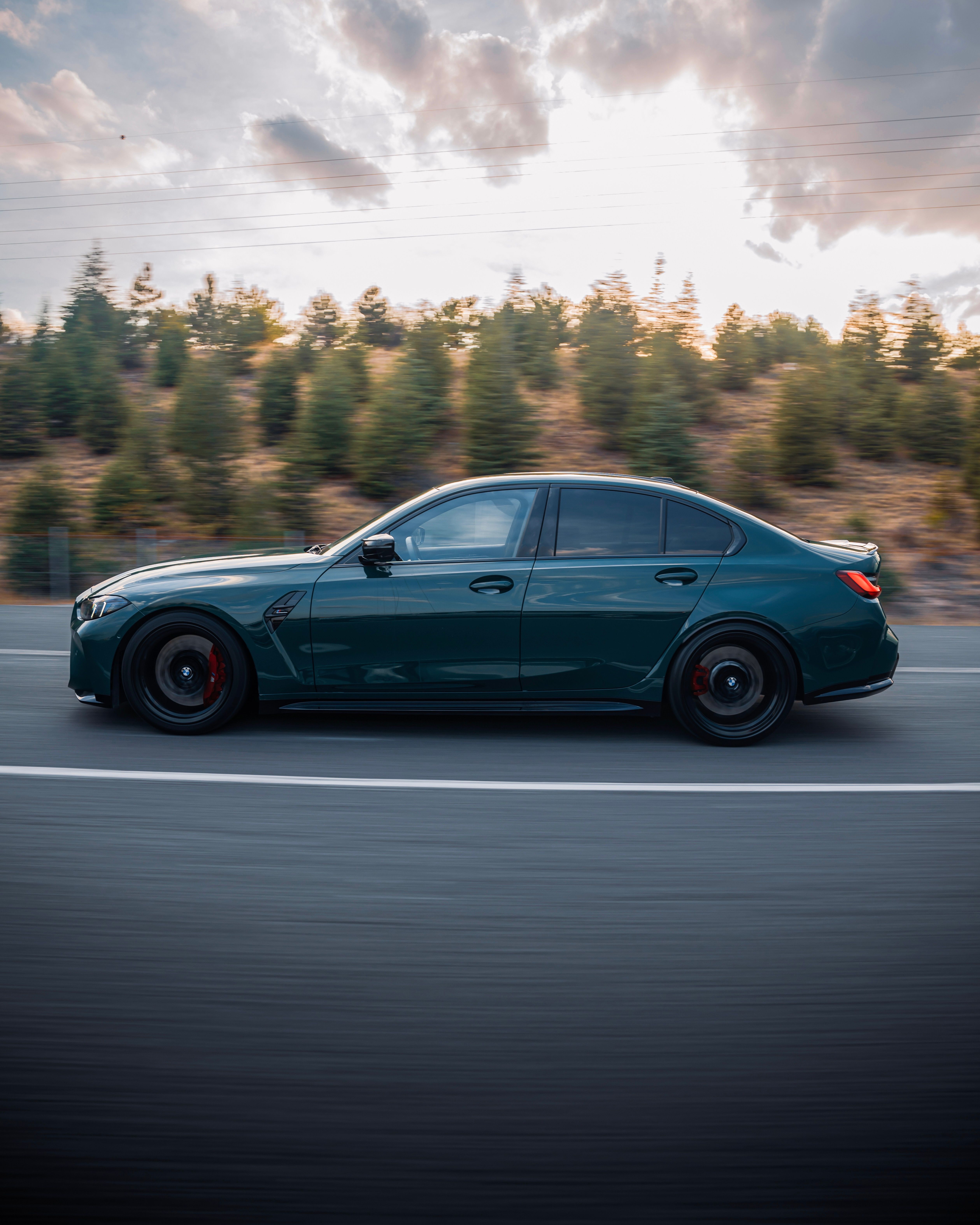 Sleek Black Sedan Driving Through Forest Road · Free Stock Photo