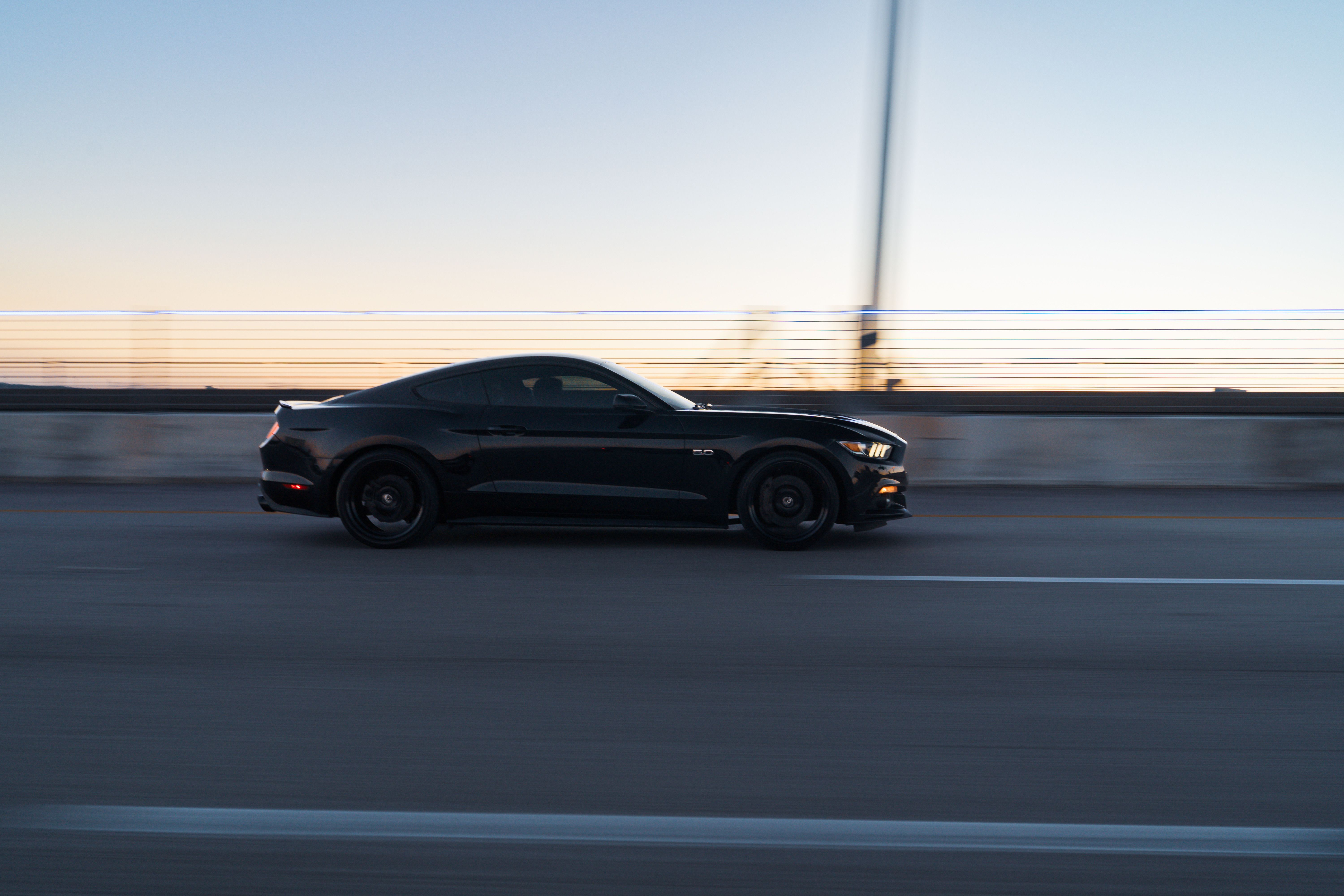 Sleek Black Car Speeding on Highway at Dusk · Free Stock Photo