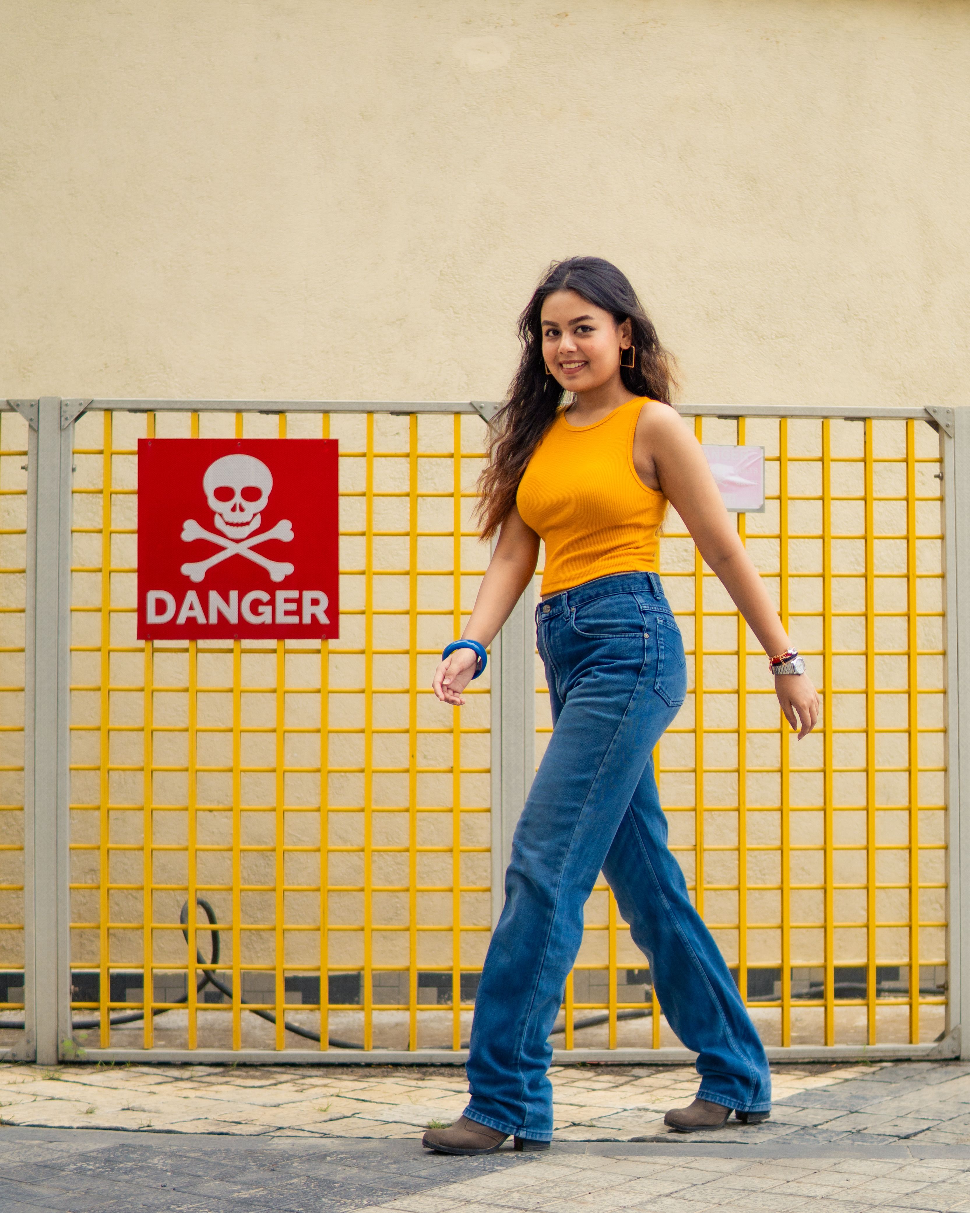Young Woman Walking Past Danger Sign Outdoors · Free Stock Photo