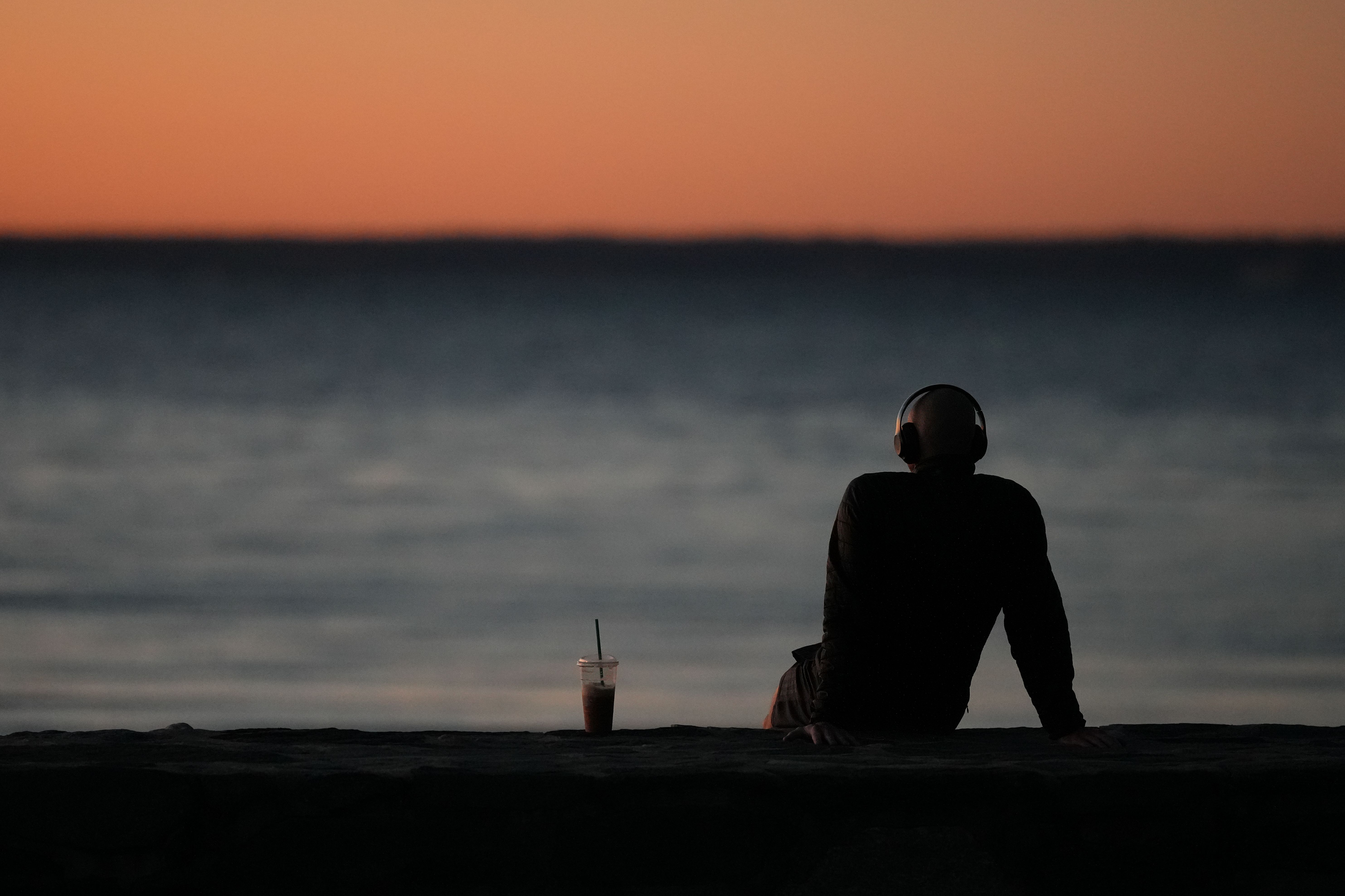 Silhouetted Figure Relaxing at Dawn by the Water · Free Stock Photo