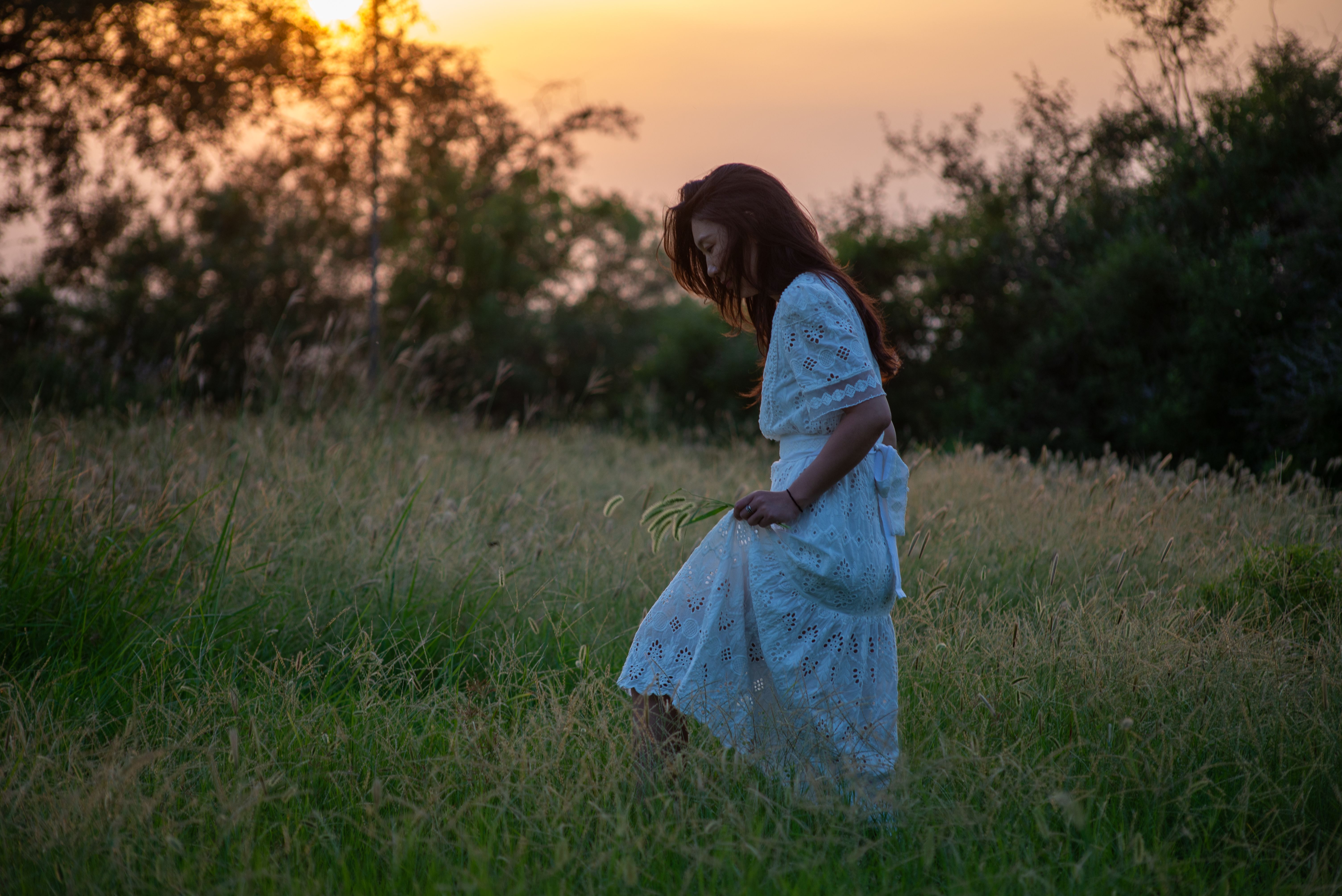 Woman in White Dress Walking Through Meadow at Sunset · Free Stock Photo