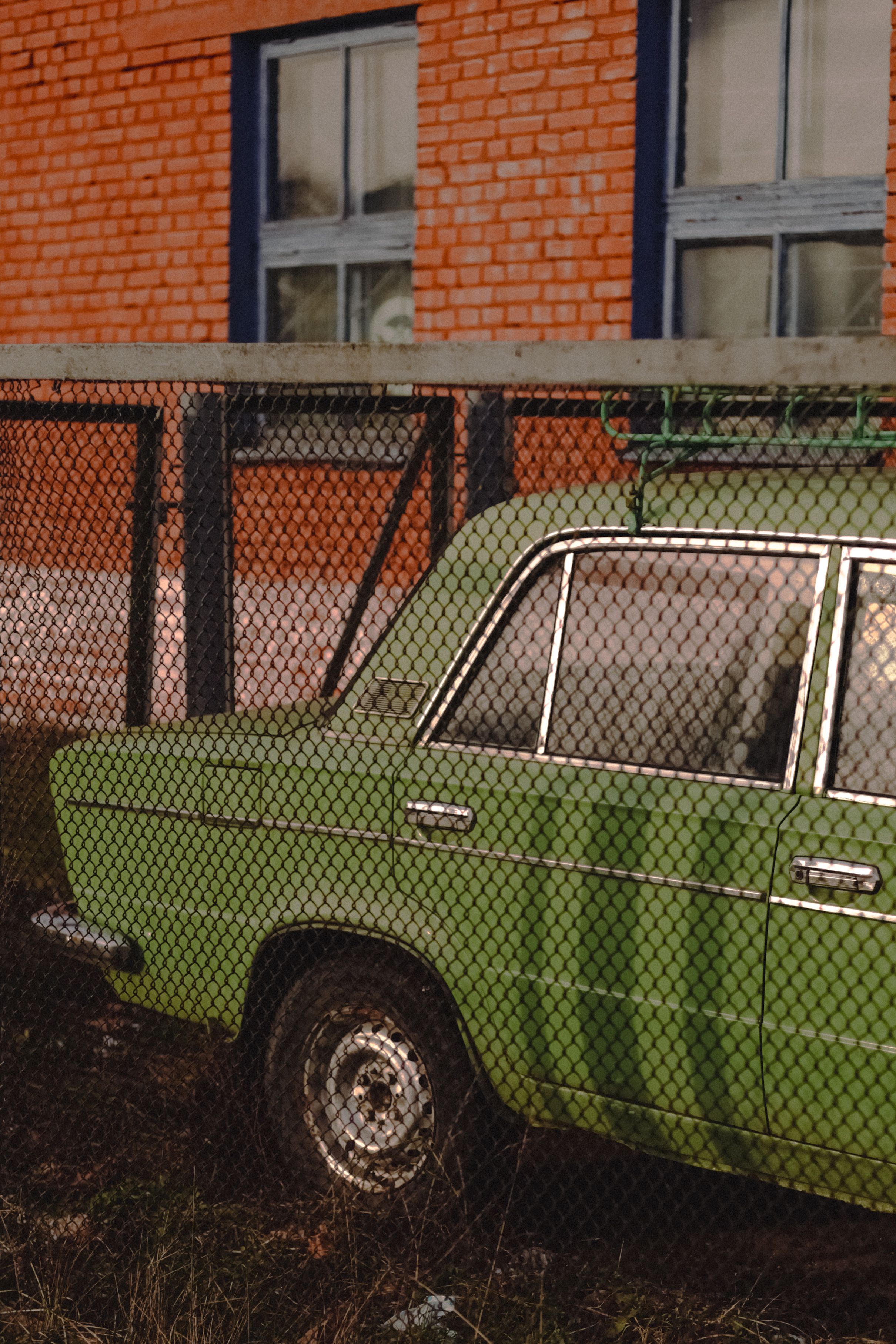 Vintage Green Car Behind Chain-Link Fence · Free Stock Photo
