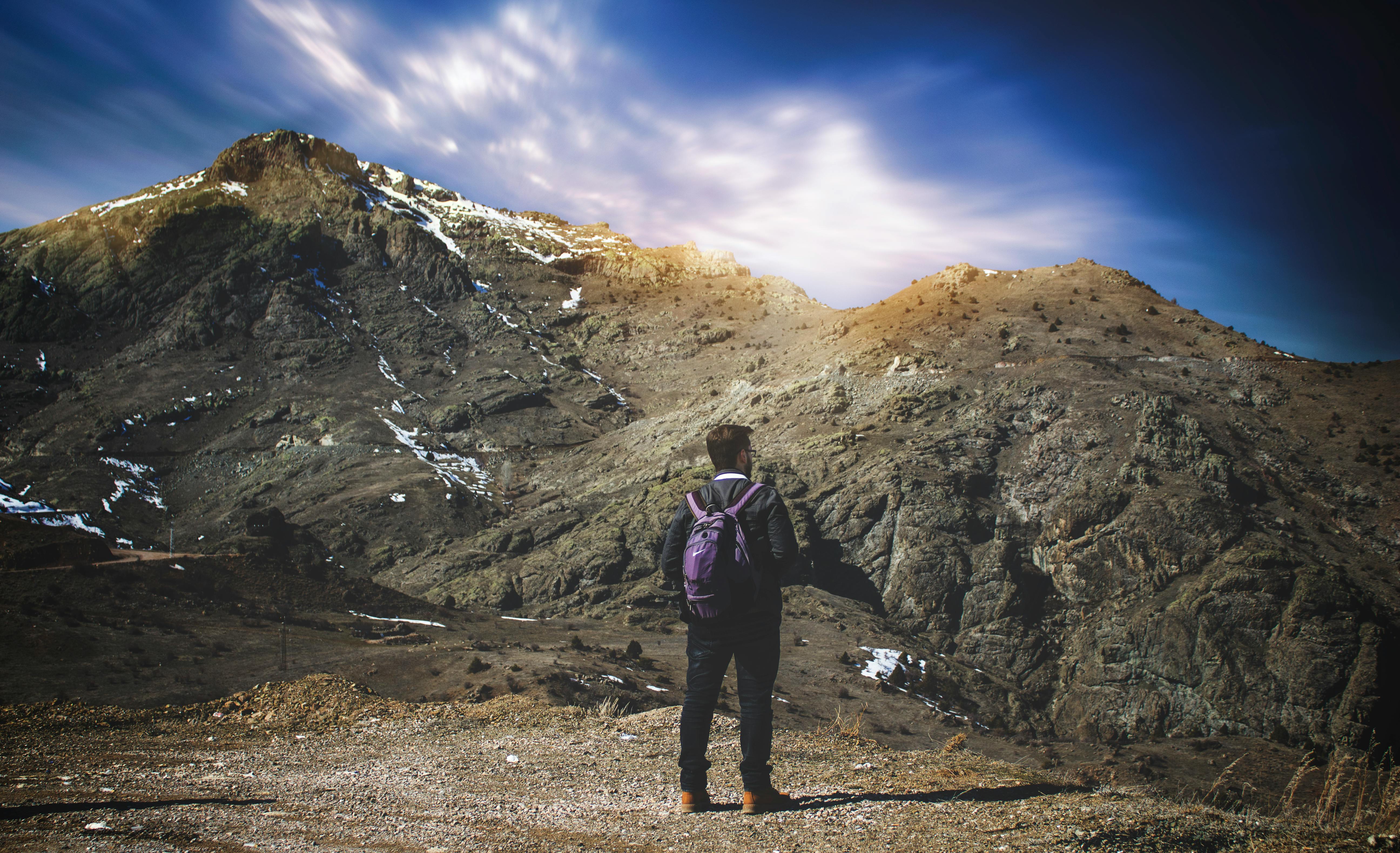 Man Carrying Backpack Standing on Rock Formation · Free Stock Photo