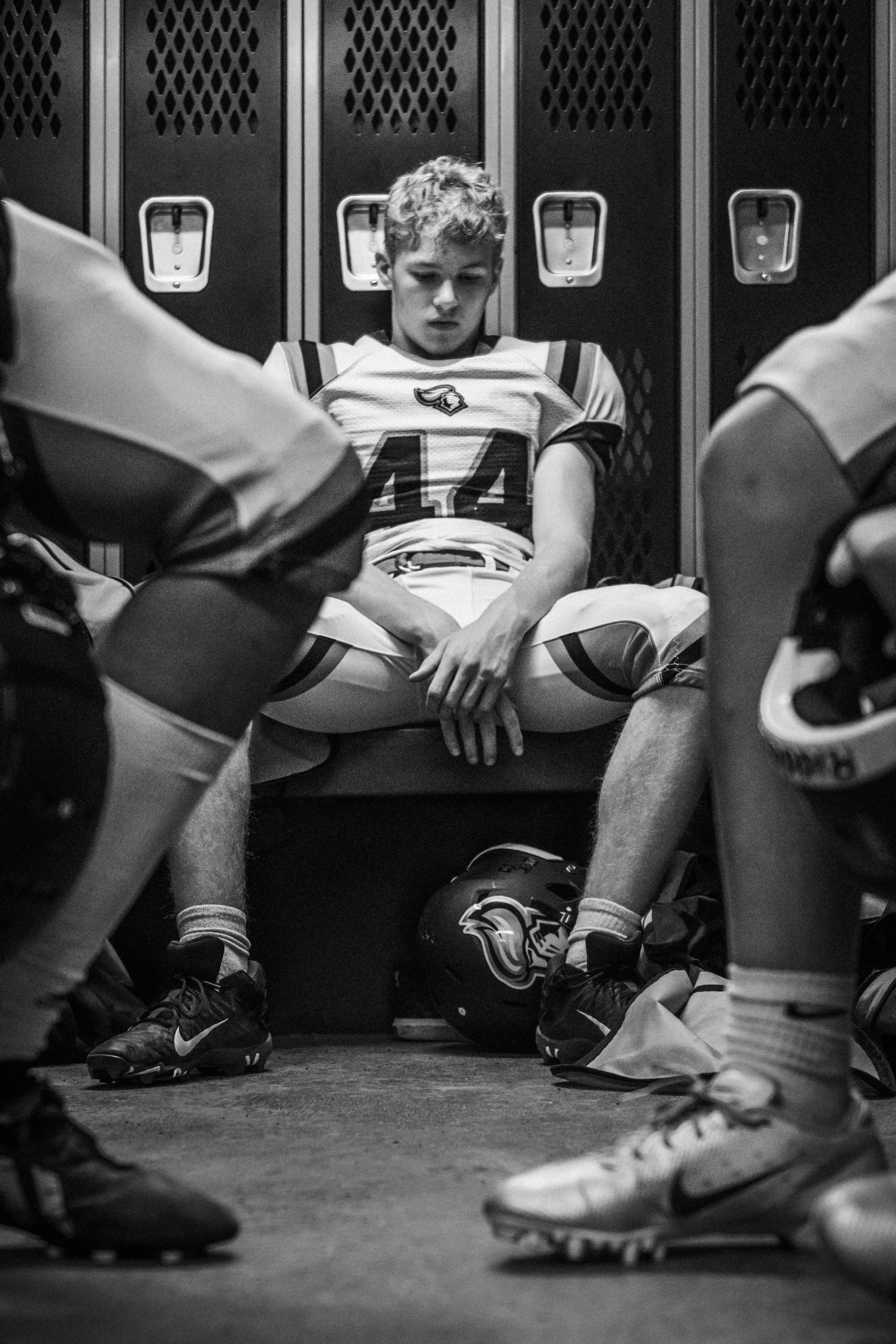High School Football Player Resting in Locker Room · Free Stock Photo