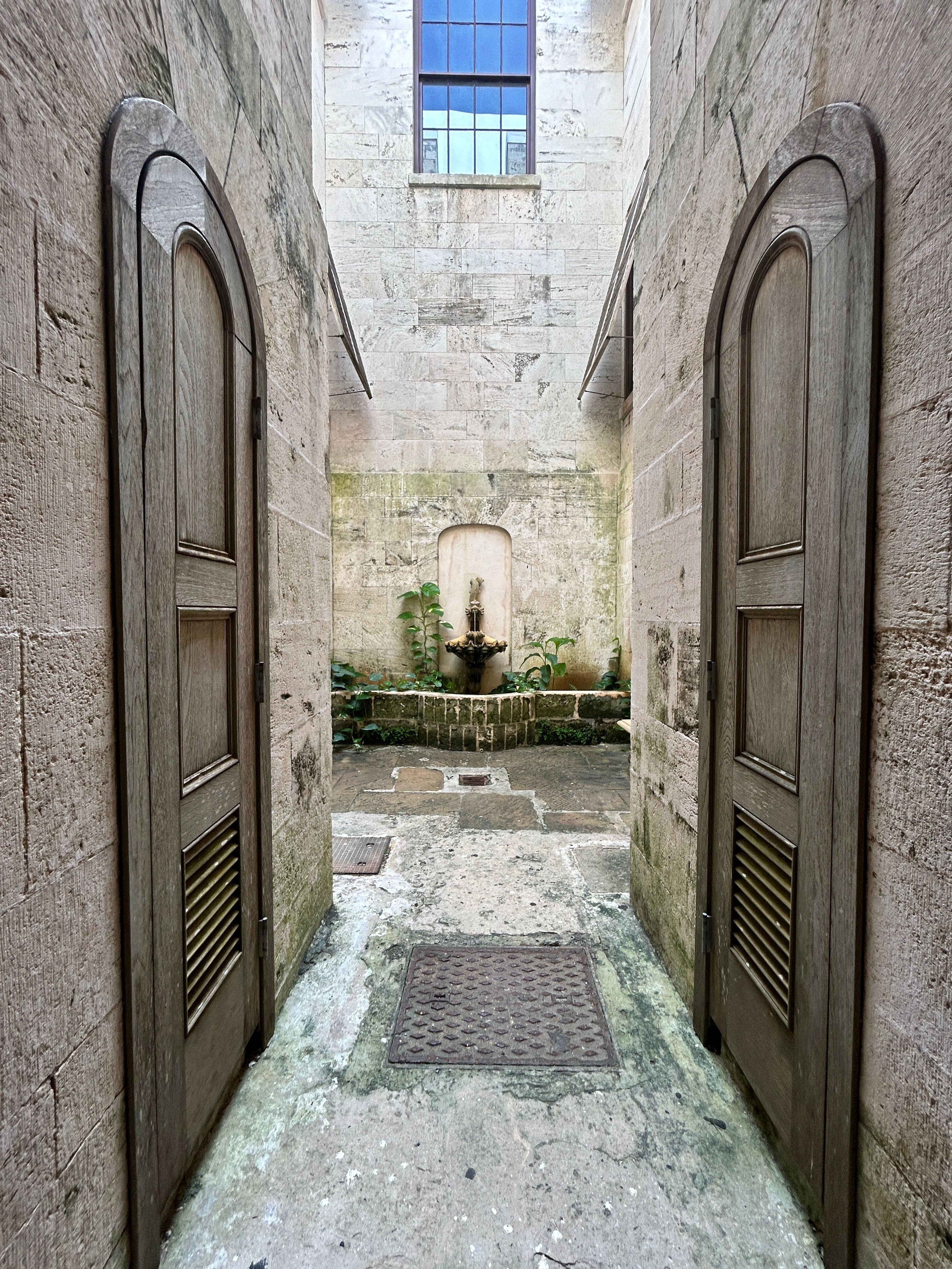 Rustic Courtyard with Wooden Doors and Fountain · Free Stock Photo