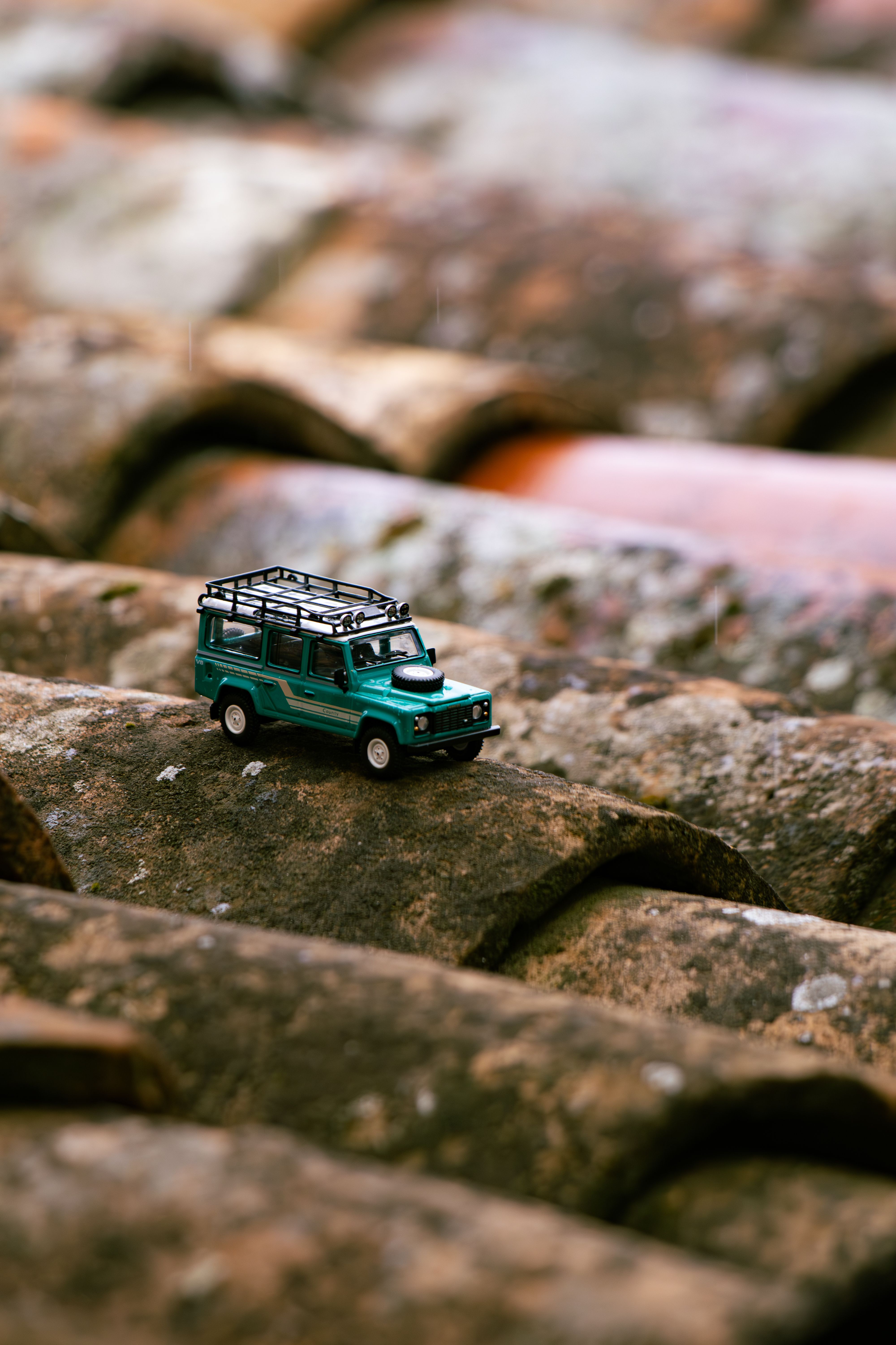 Miniature Green SUV on Rustic Roof Tiles · Free Stock Photo