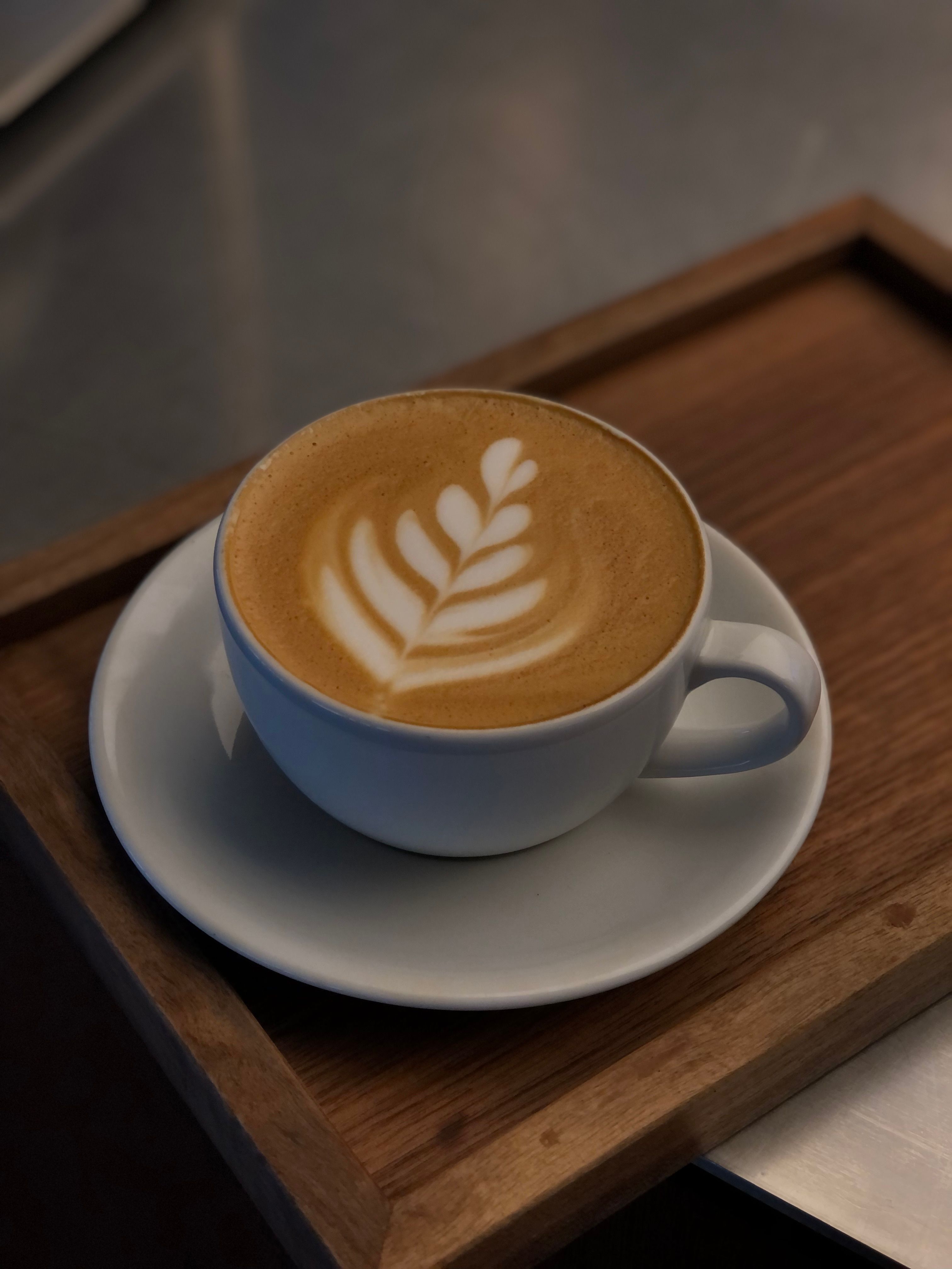 Latte art in cup of coffee on a Round Table · Free Stock Photo