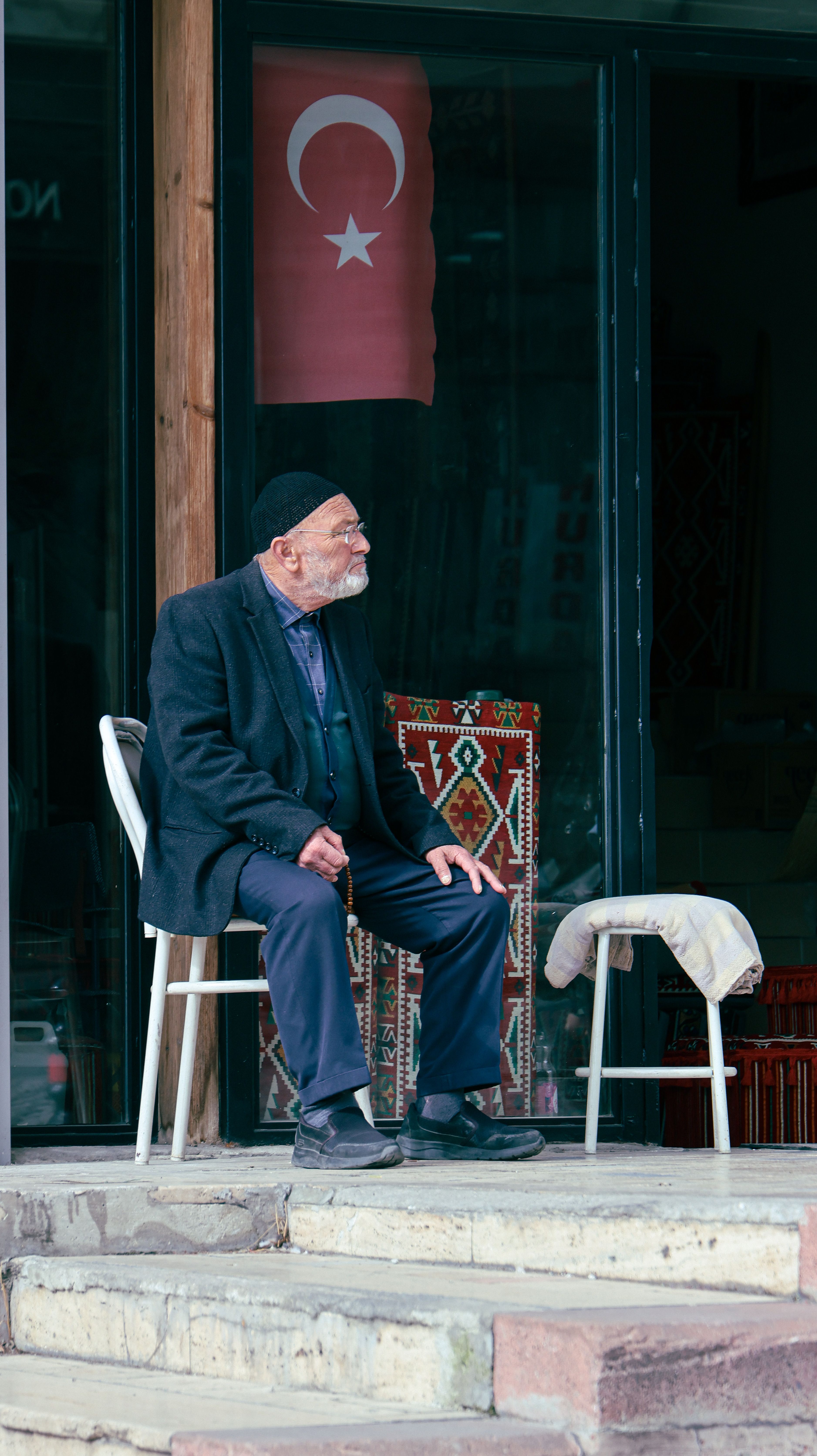 Elderly Man Sitting Outside Shop with Turkish Flag · Free Stock Photo