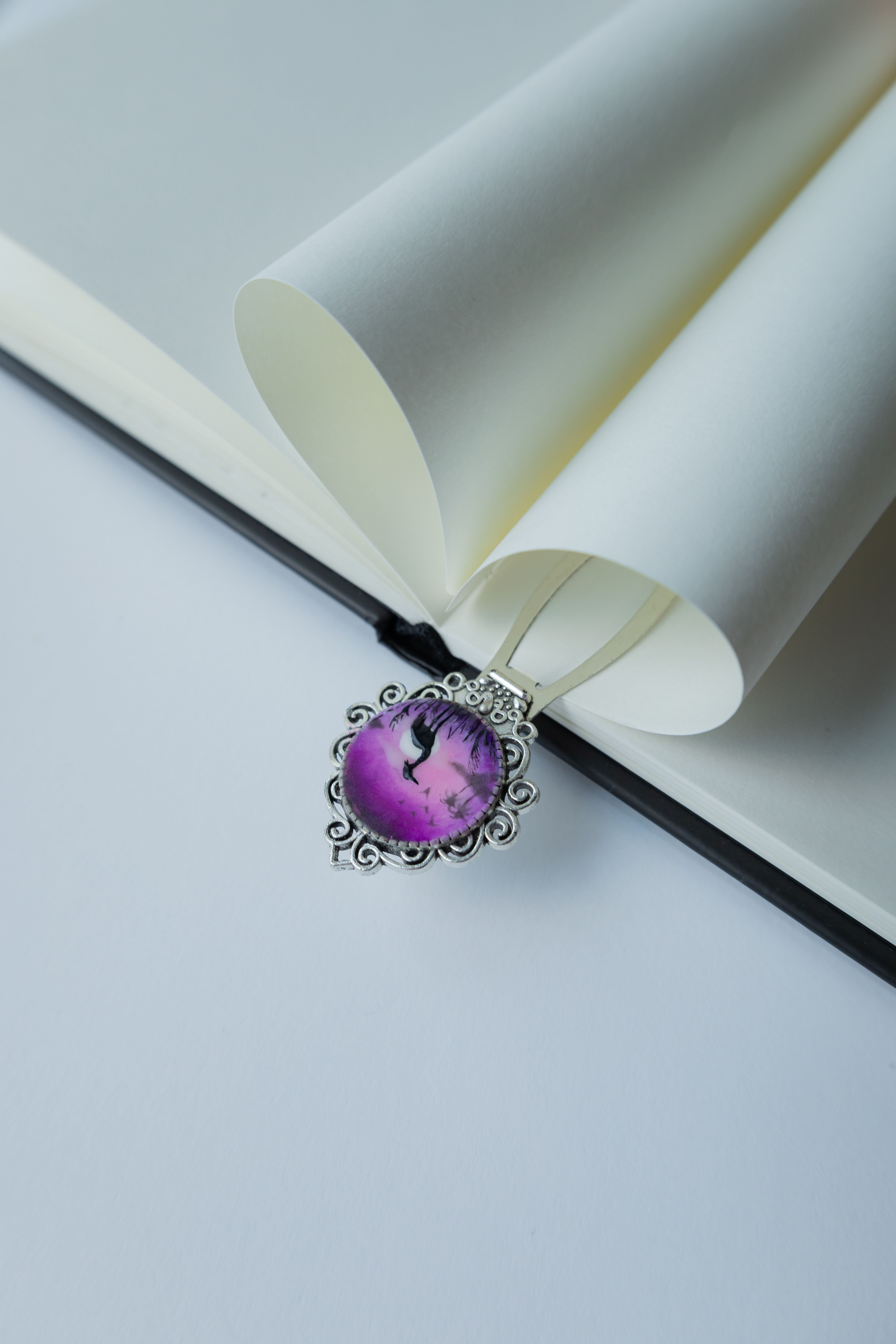 Elegant Bookmark with Violet Cameo on Open Book · Free Stock Photo