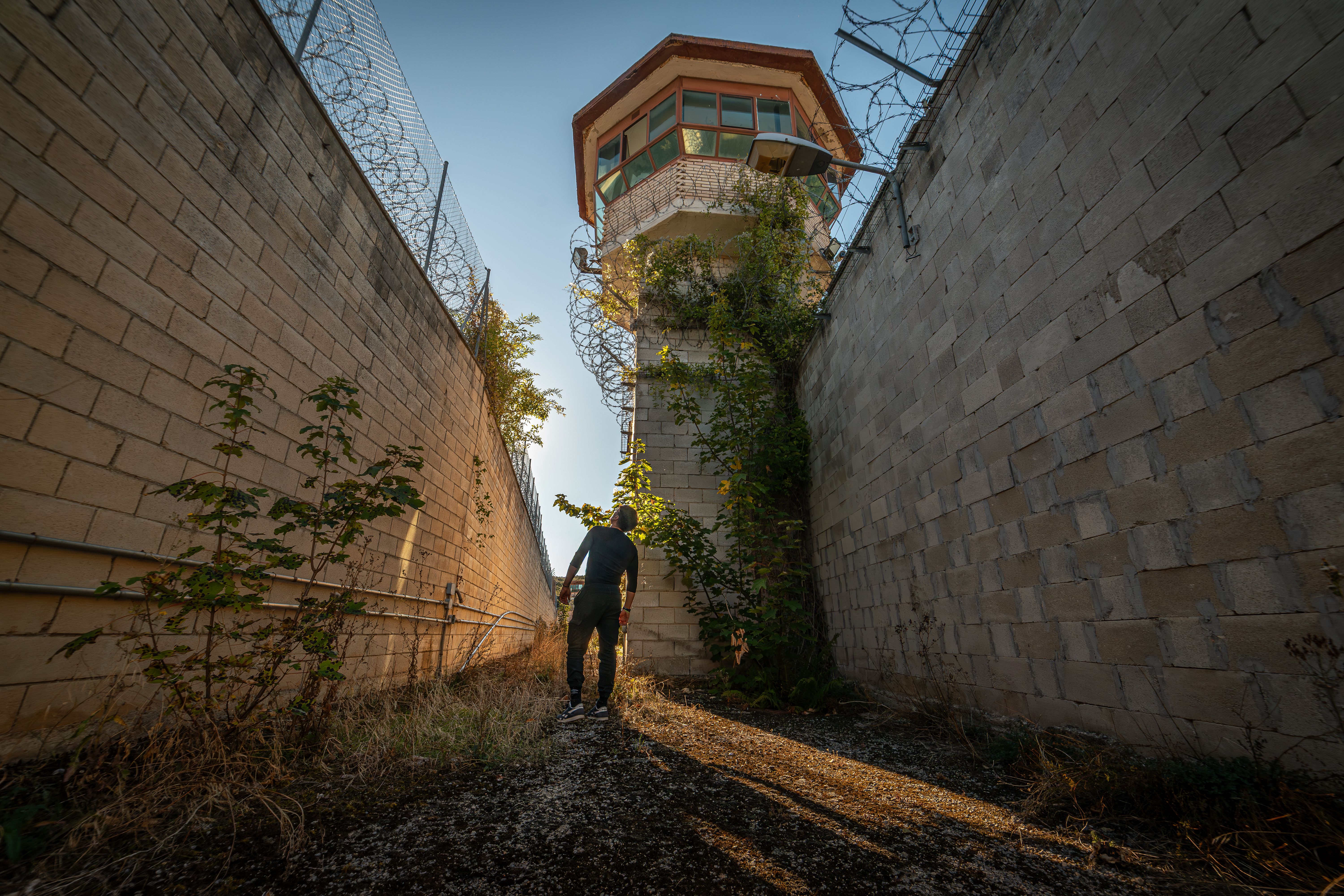 Man Exploring Abandoned Prison Courtyard · Free Stock Photo