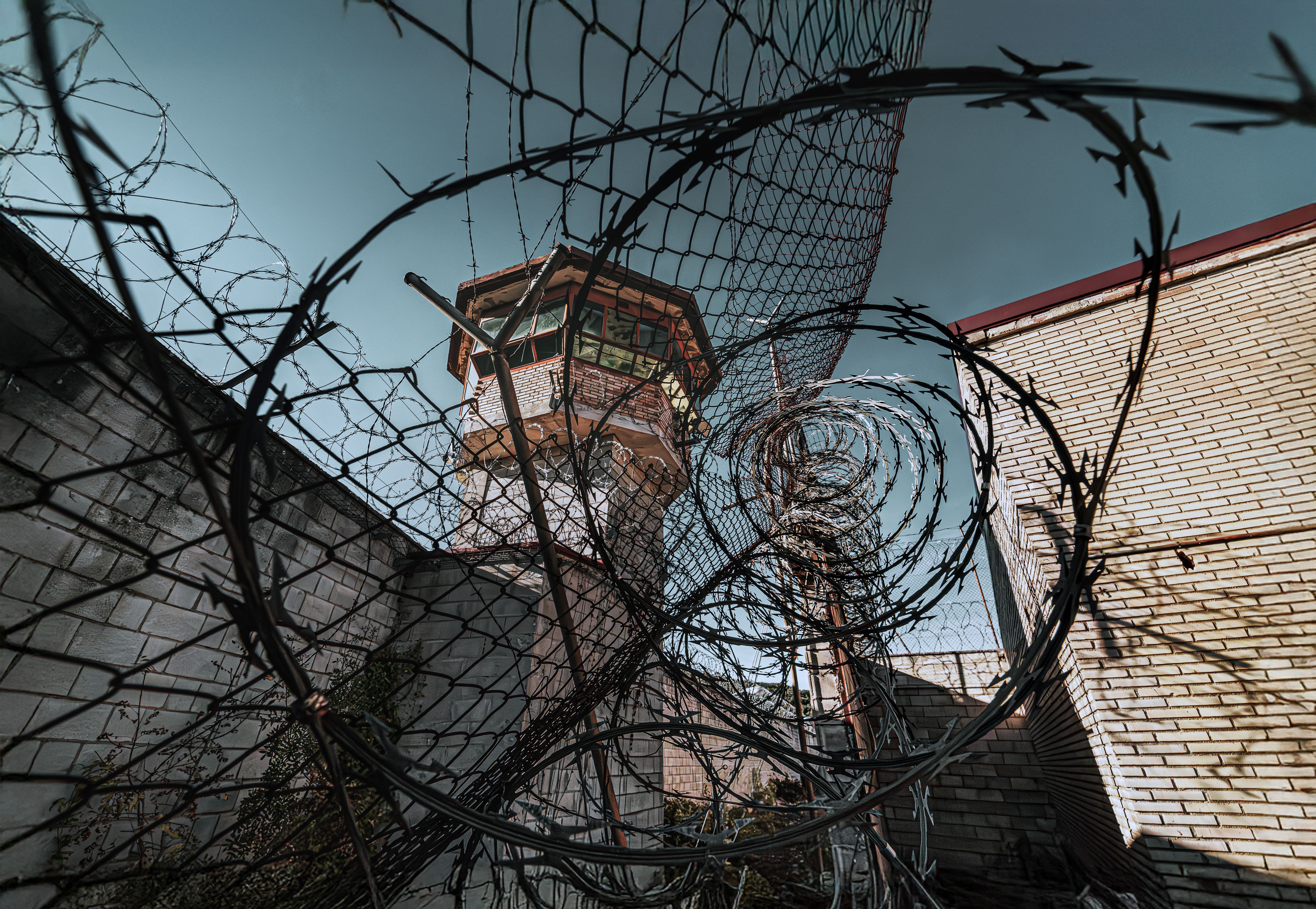 Barbed Wire Fence and Guard Tower in Prison Yard · Free Stock Photo