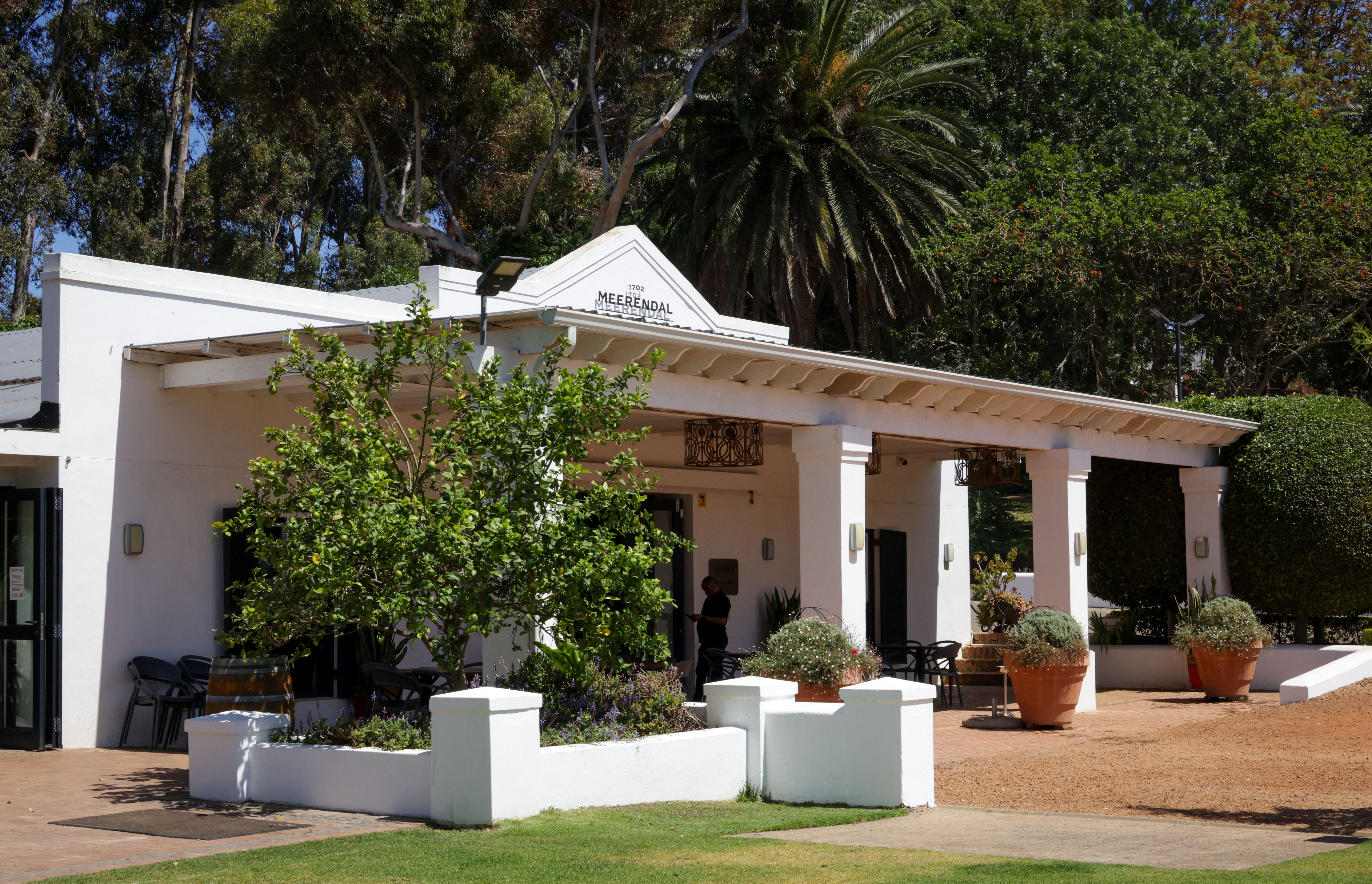 White Colonial-Style Building in Sunny Garden Setting · Free Stock Photo