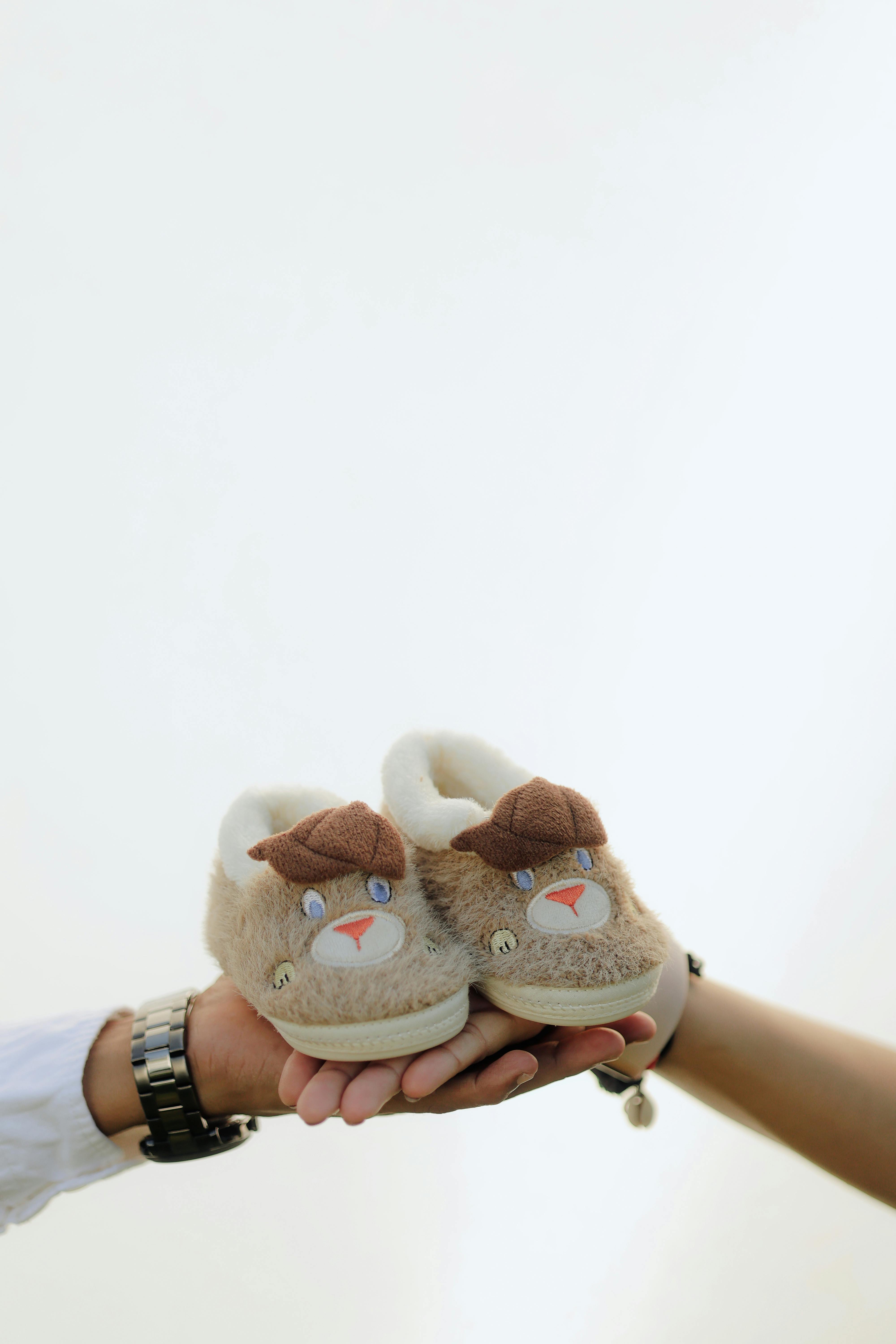 Cute Baby Booties Held by Two Hands · Free Stock Photo