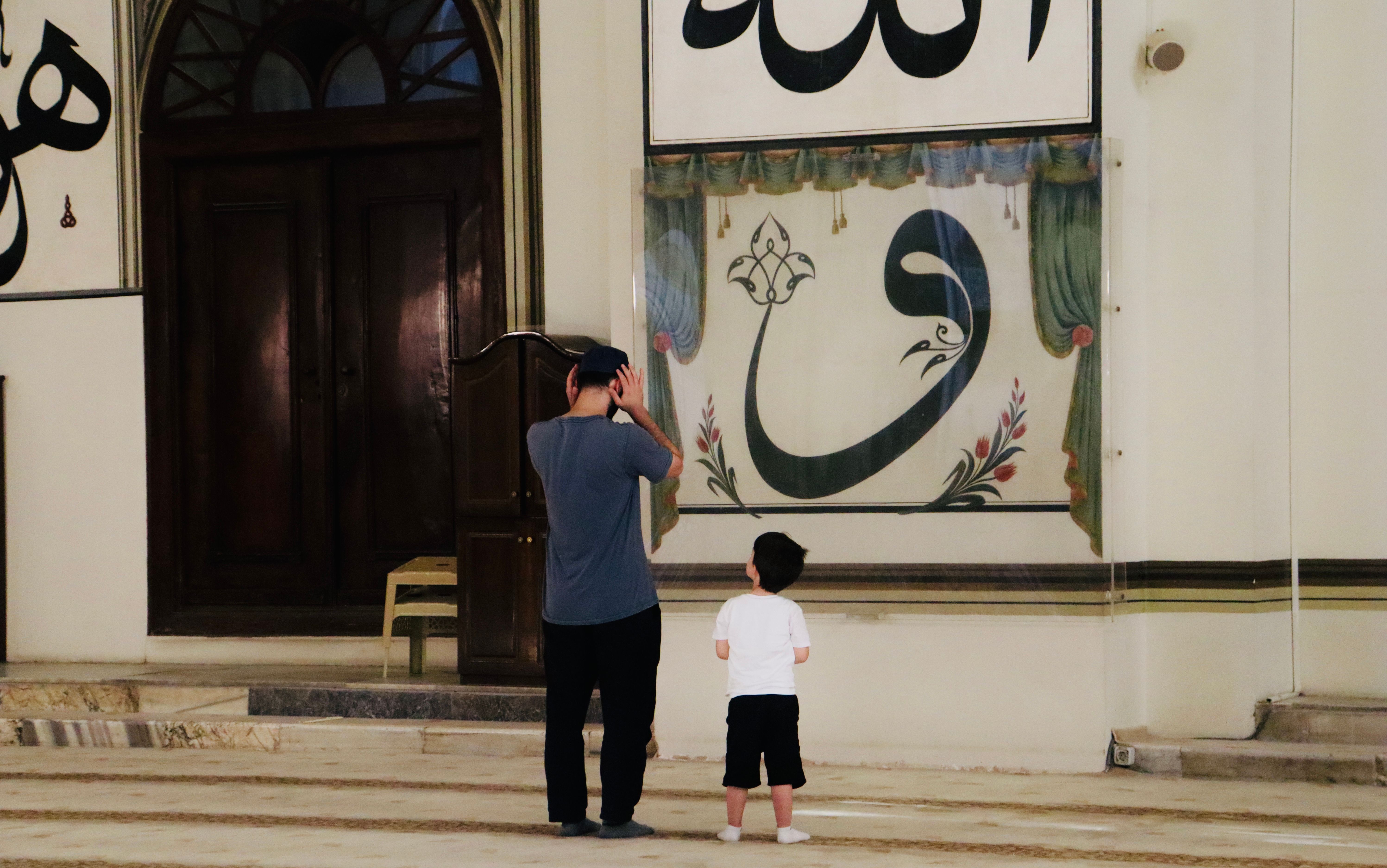Father and Son Observing Arabic Calligraphy Indoors · Free Stock Photo