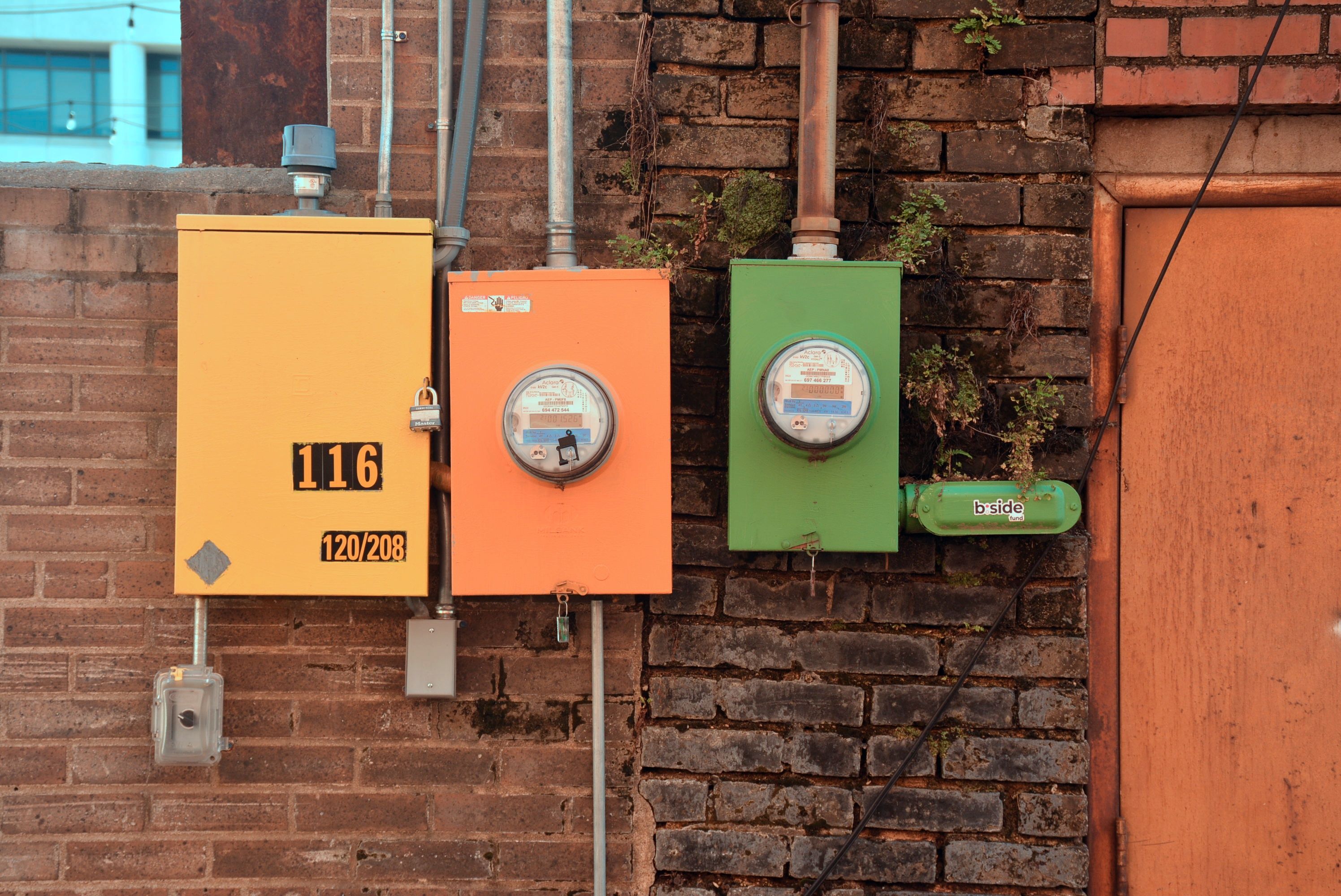 Colorful Utility Boxes on a Brick Wall Outdoors · Free Stock Photo