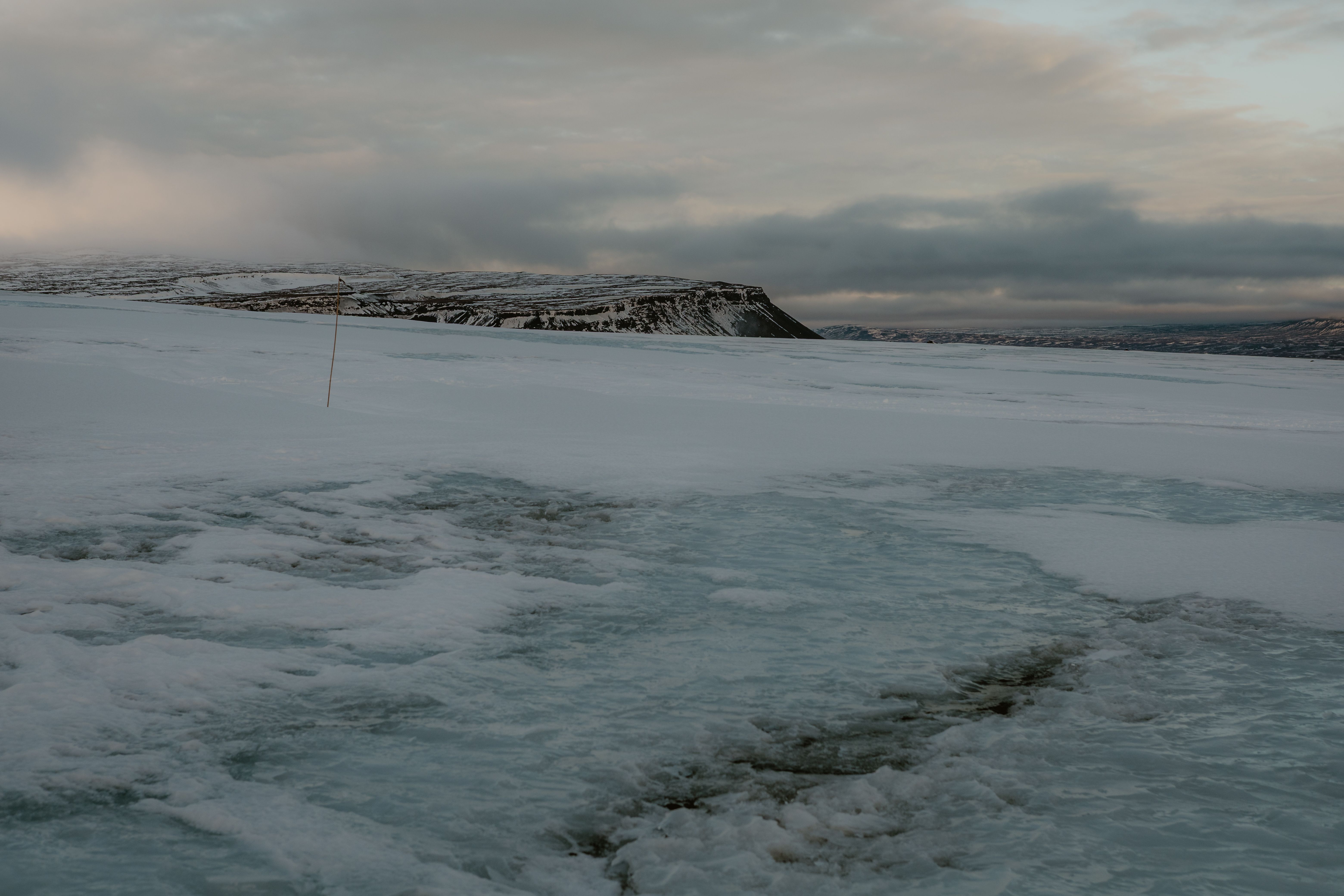 Icy Landscape with Expansive Snowfield and Cloudy Sky · Free Stock Photo
