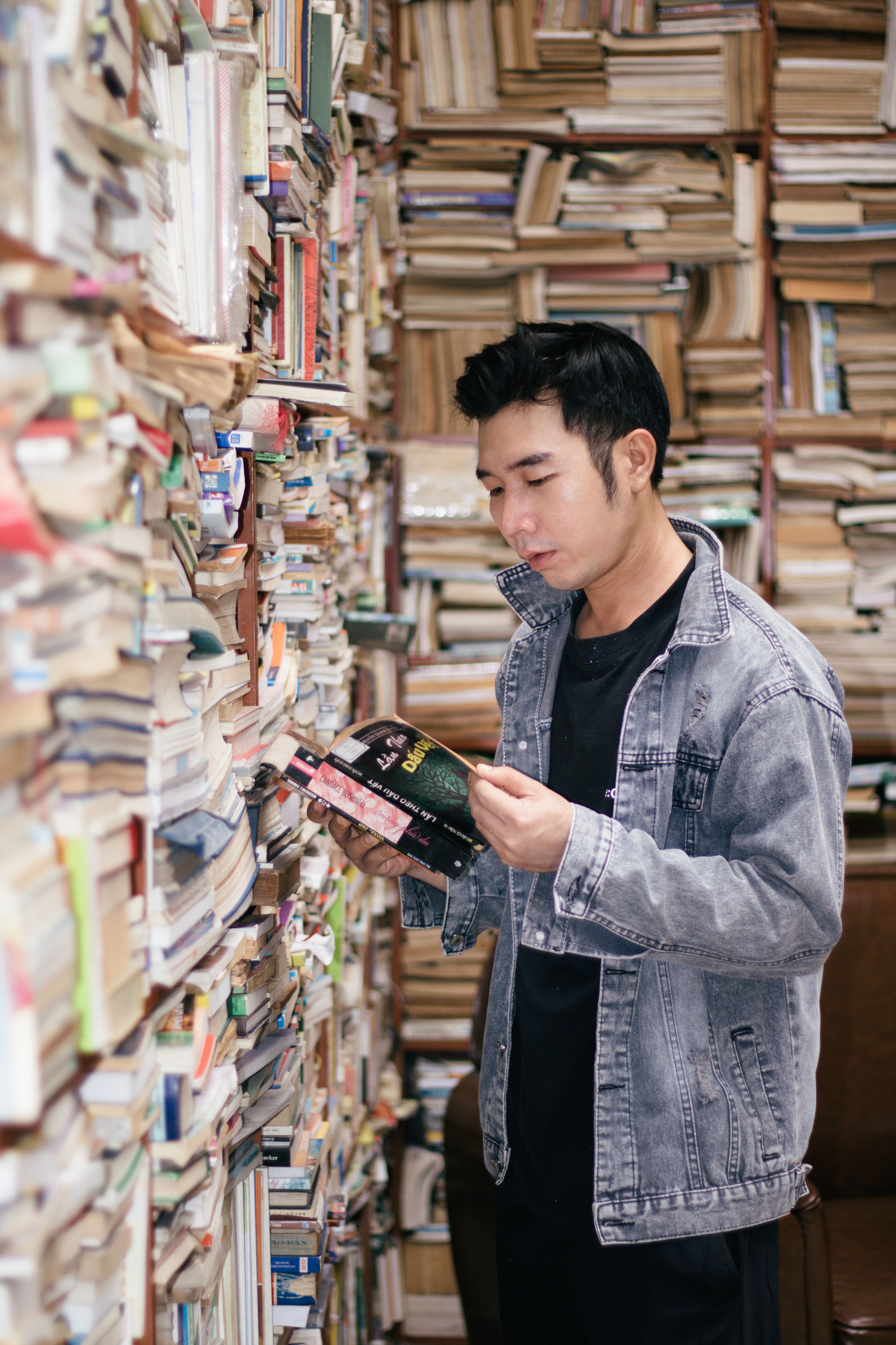 Young man reading in crowded bookstore aisle · Free Stock Photo
