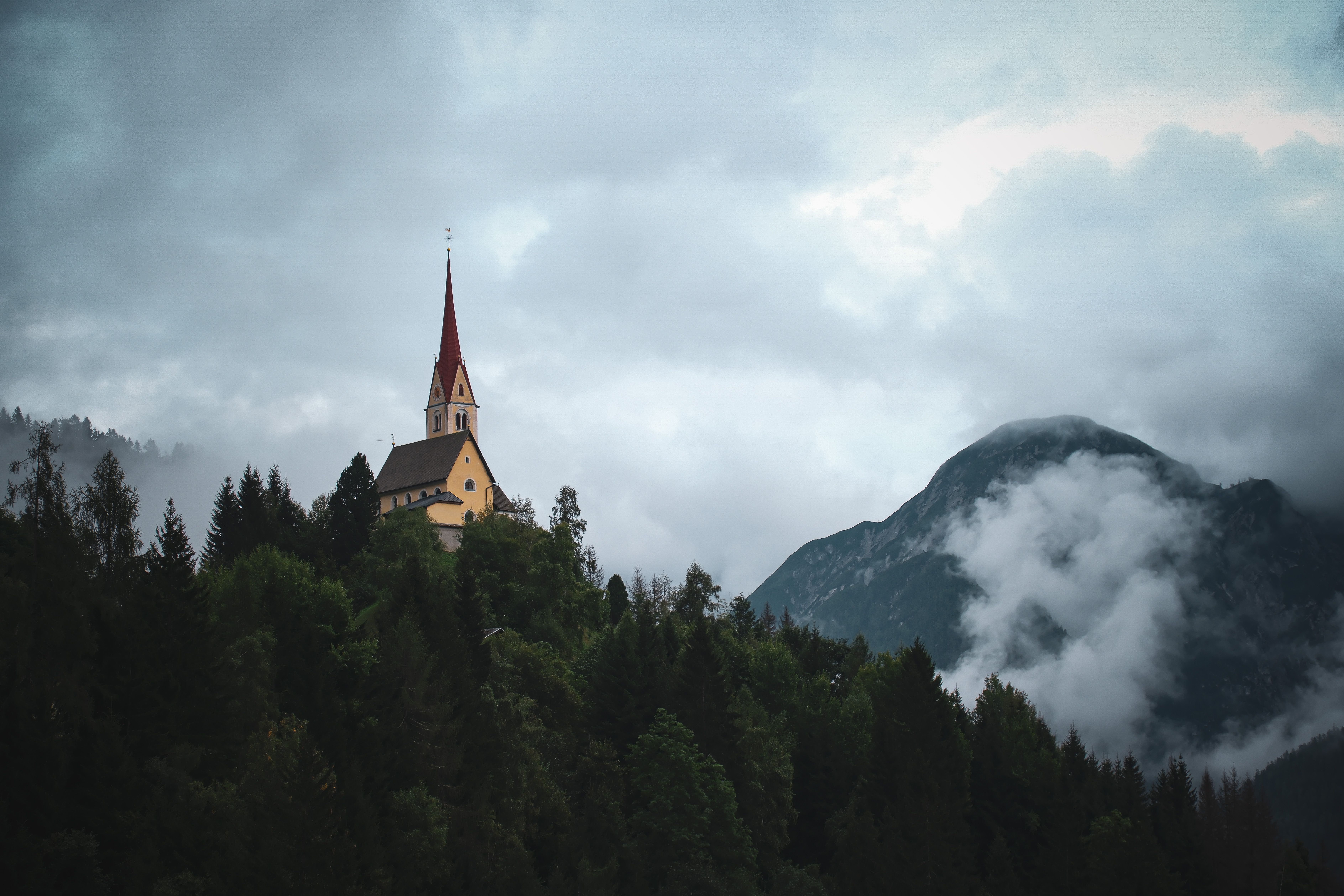 Majestic Alpine Church Amidst Cloudy Mountain Landscapes · Free Stock Photo