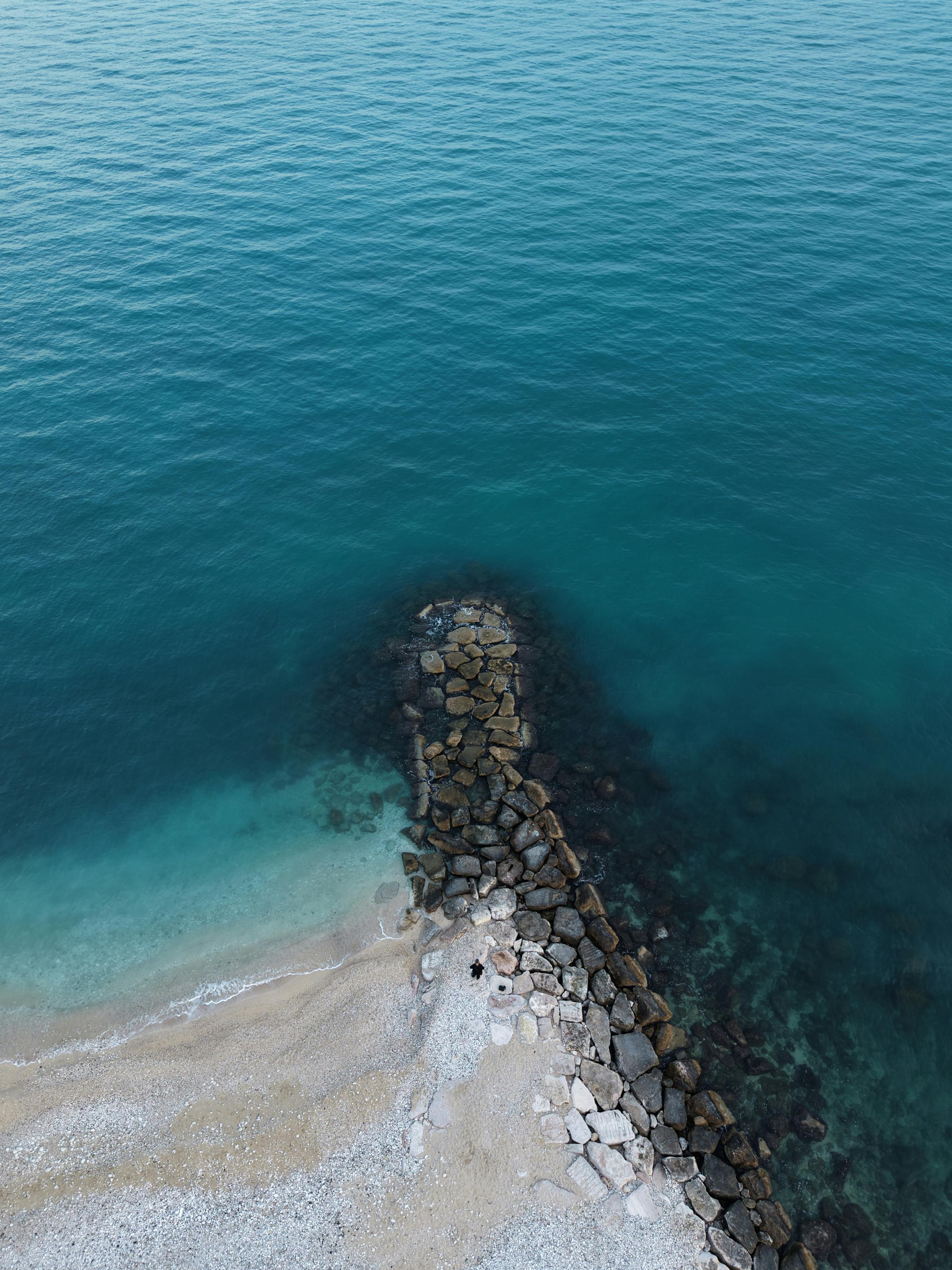Aerial View of Stone Jetty Extending into Turquoise Sea · Free Stock Photo