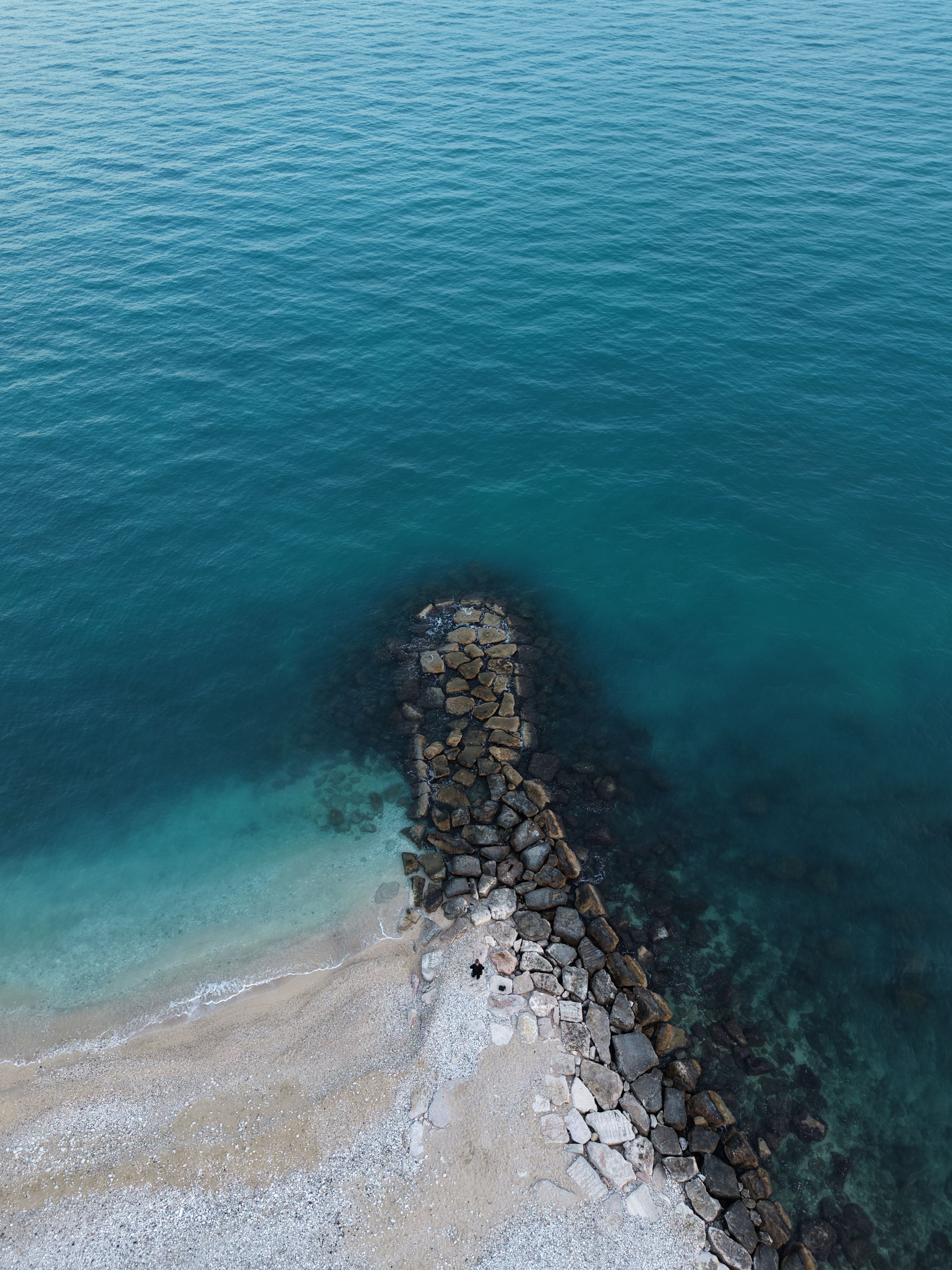 Aerial View of Stone Jetty Extending into Turquoise Sea · Free Stock Photo