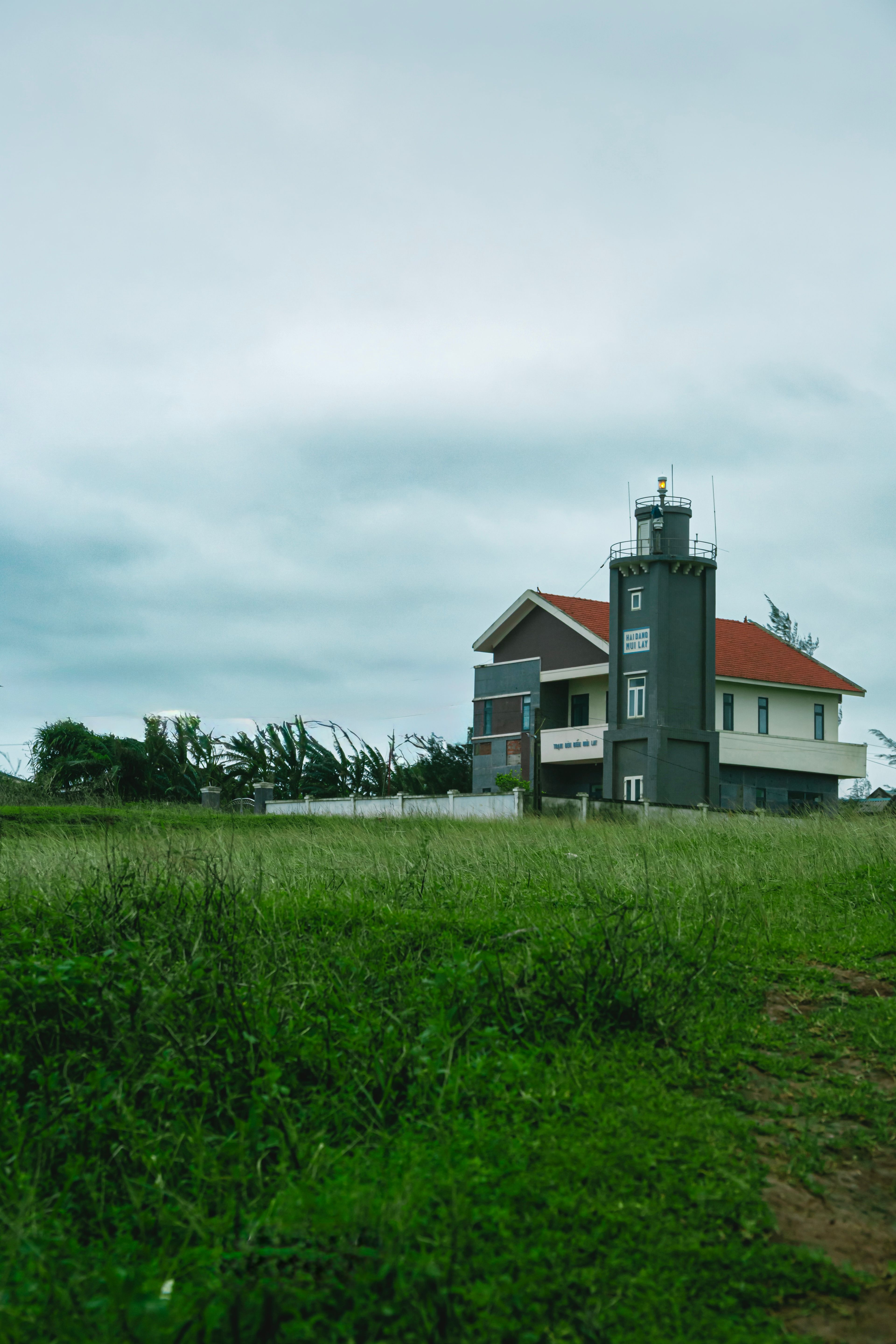 Charming Lighthouse with Red Roof in Green Field · Free Stock Photo