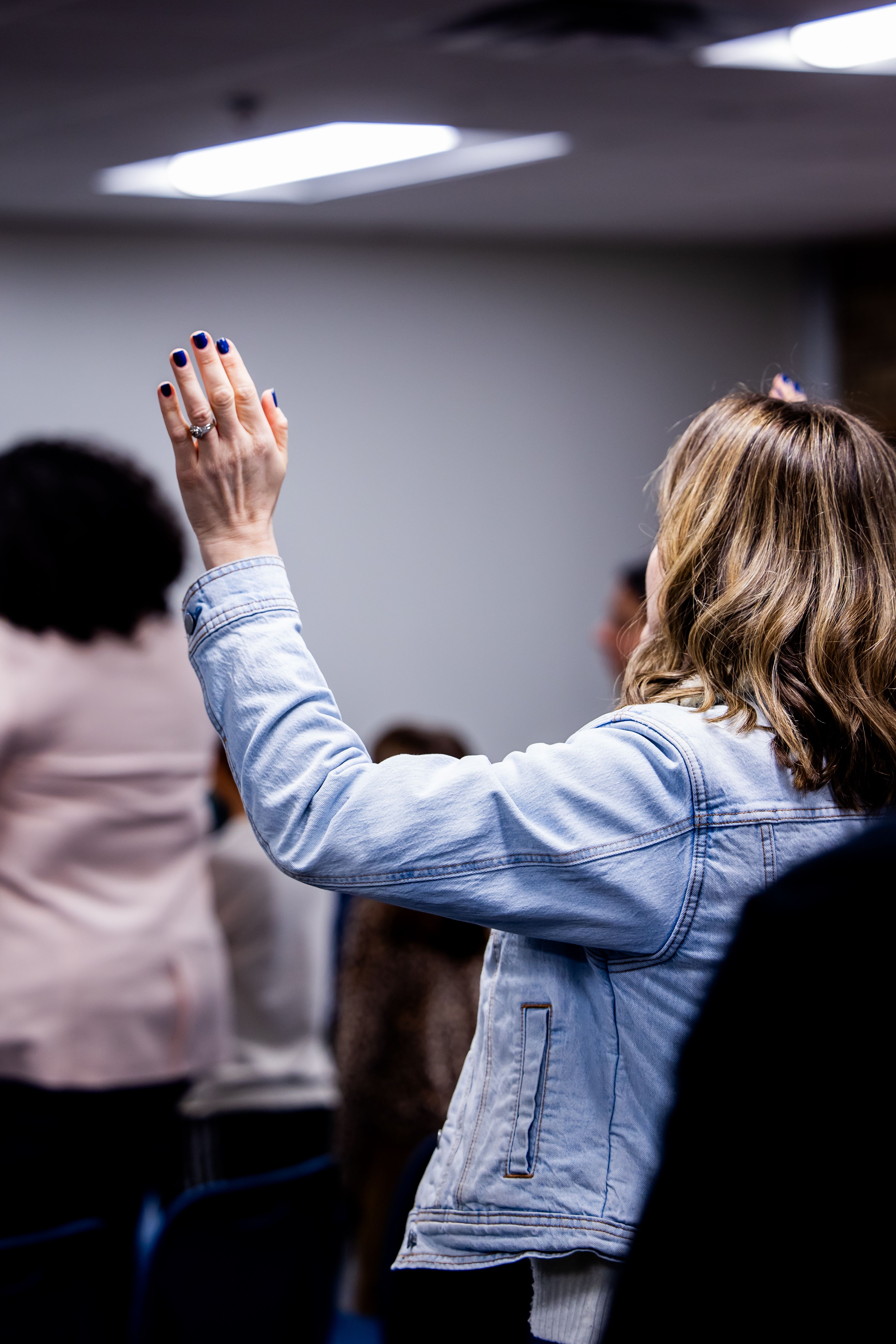 Person Raising Hand in Indoor Setting · Free Stock Photo
