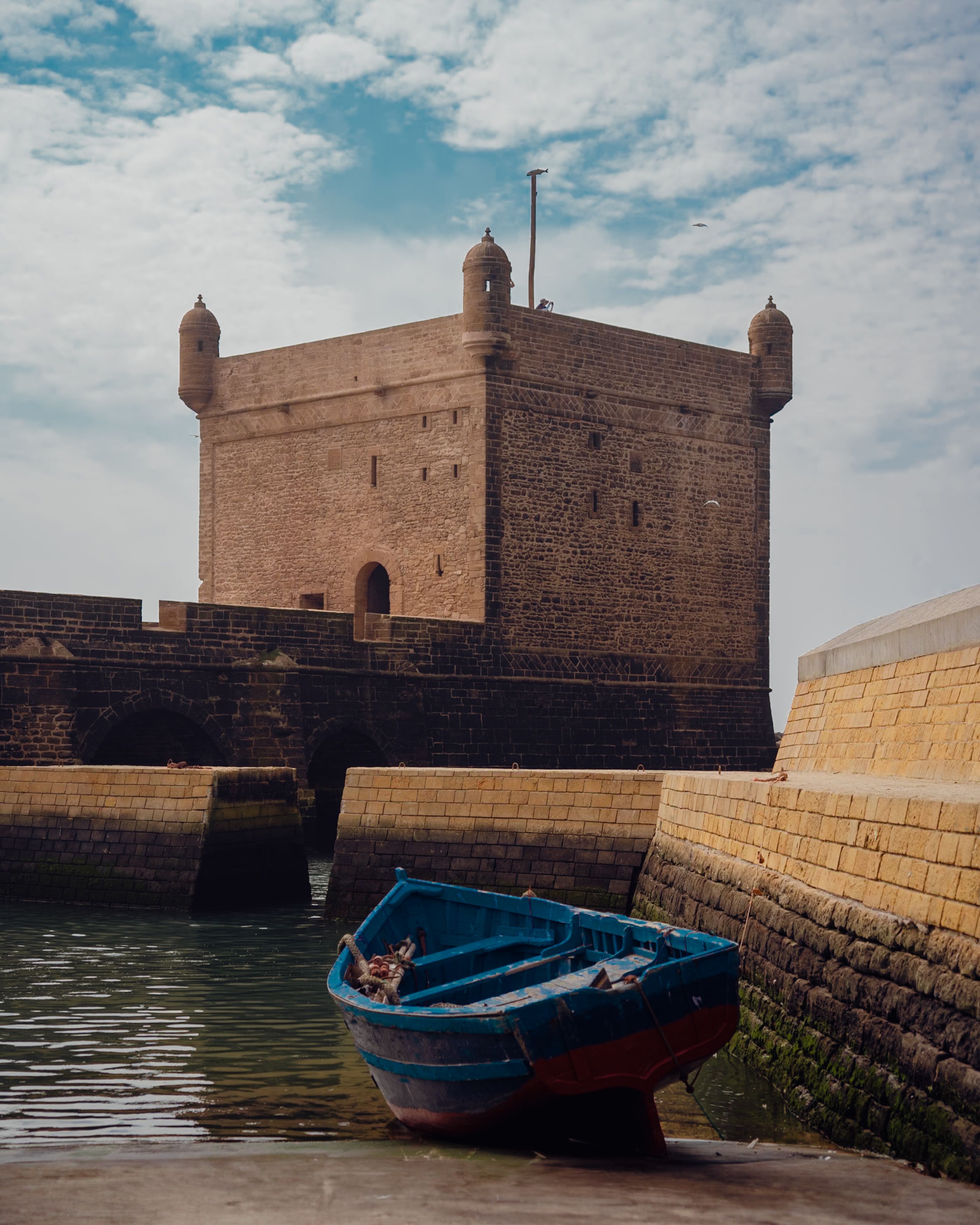 Historic Fort with Blue Boat in Essaouira Harbor · Free Stock Photo