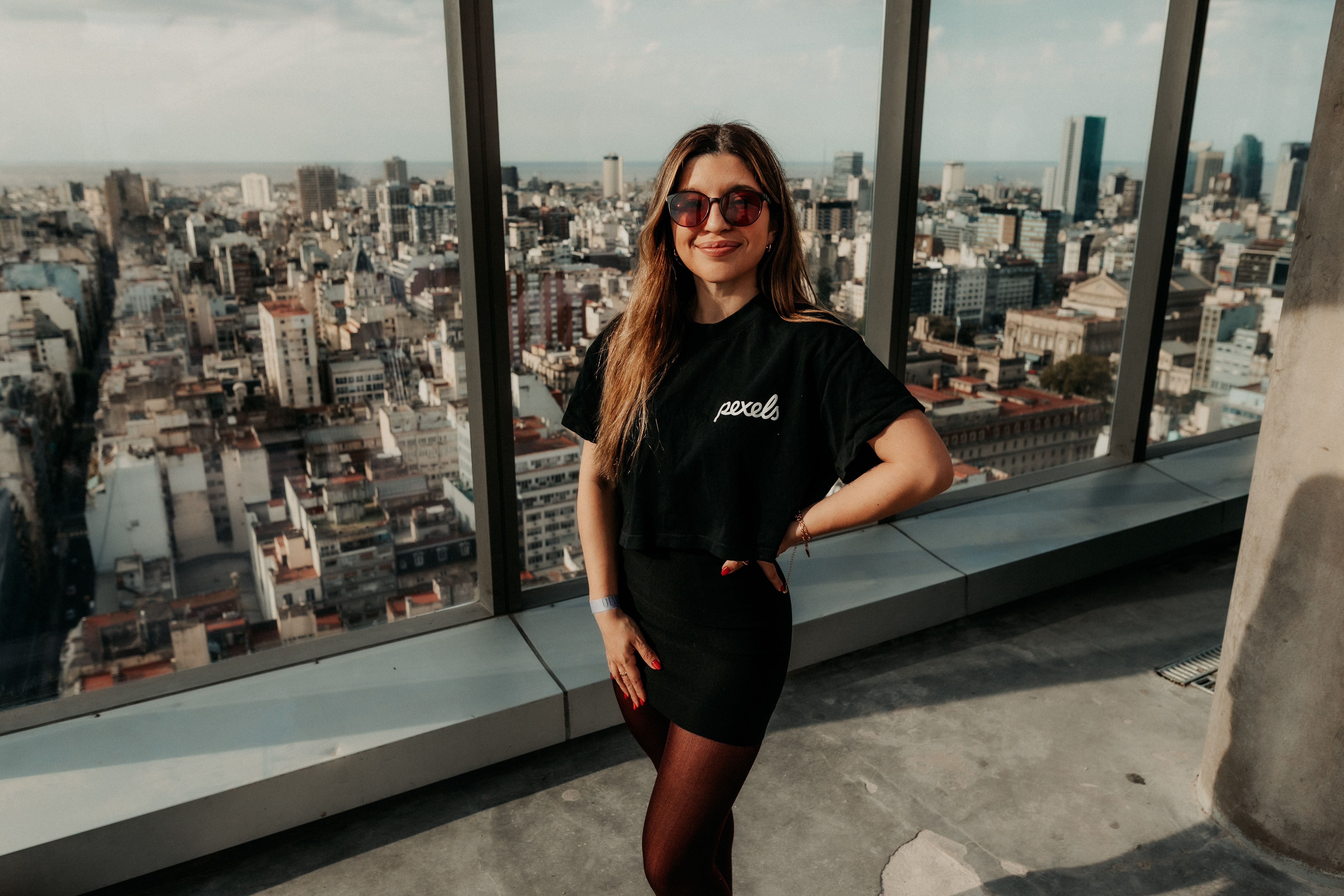 Young Woman Posing Indoors with City View · Free Stock Photo