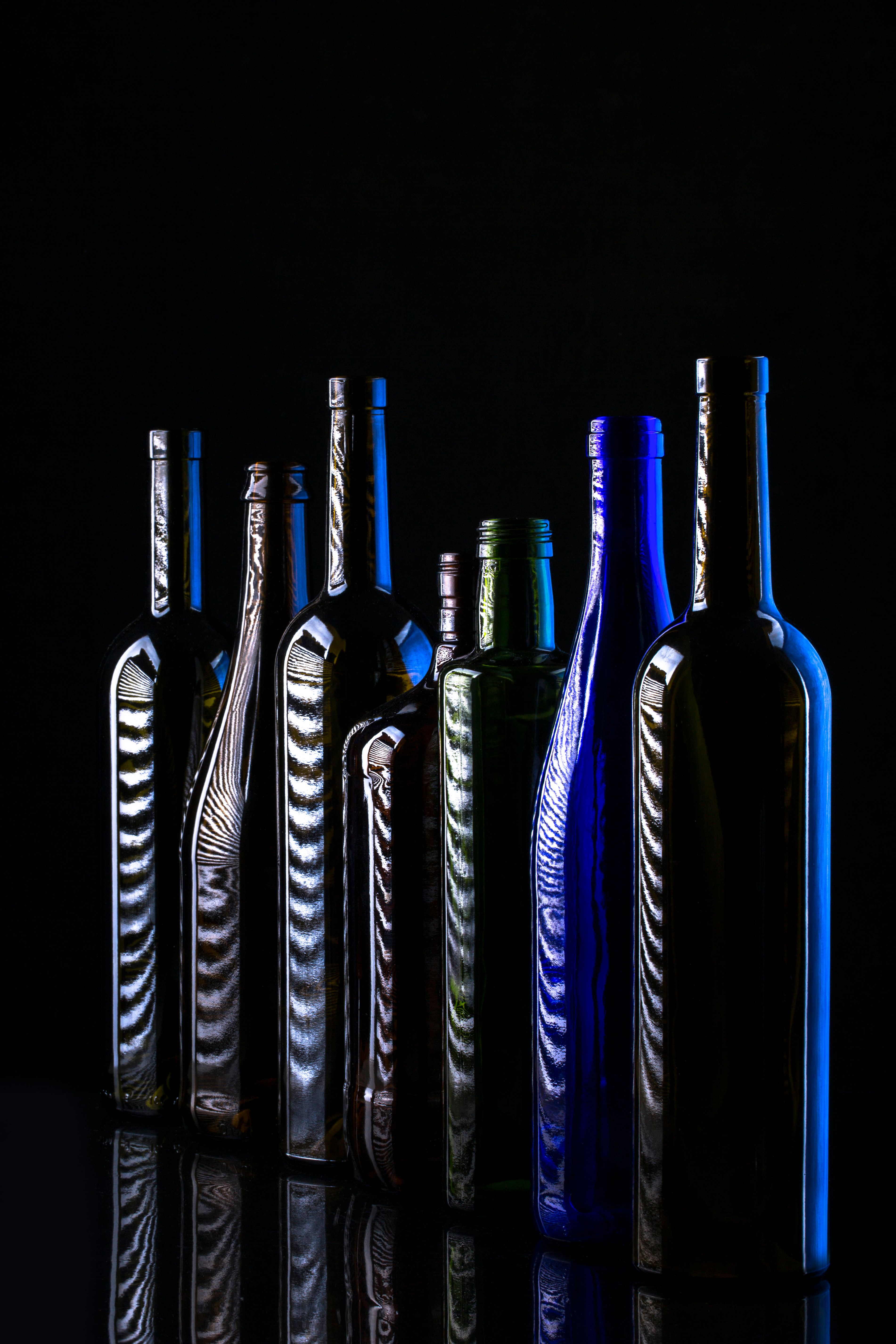 Artistic Glass Bottles on Reflective Surface · Free Stock Photo