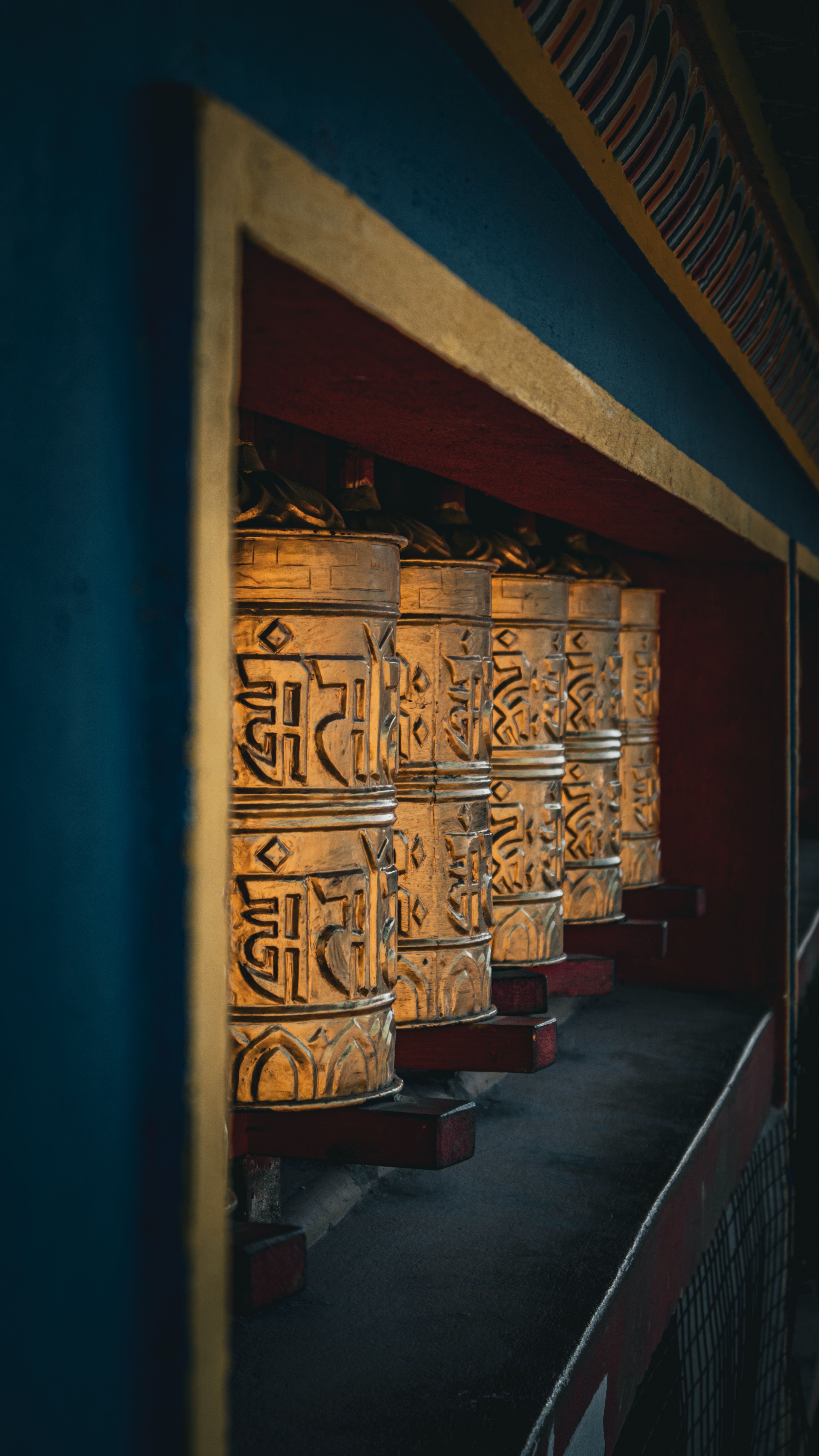 Golden Buddhist Prayer Wheels in Dimly Lit Temple · Free Stock Photo