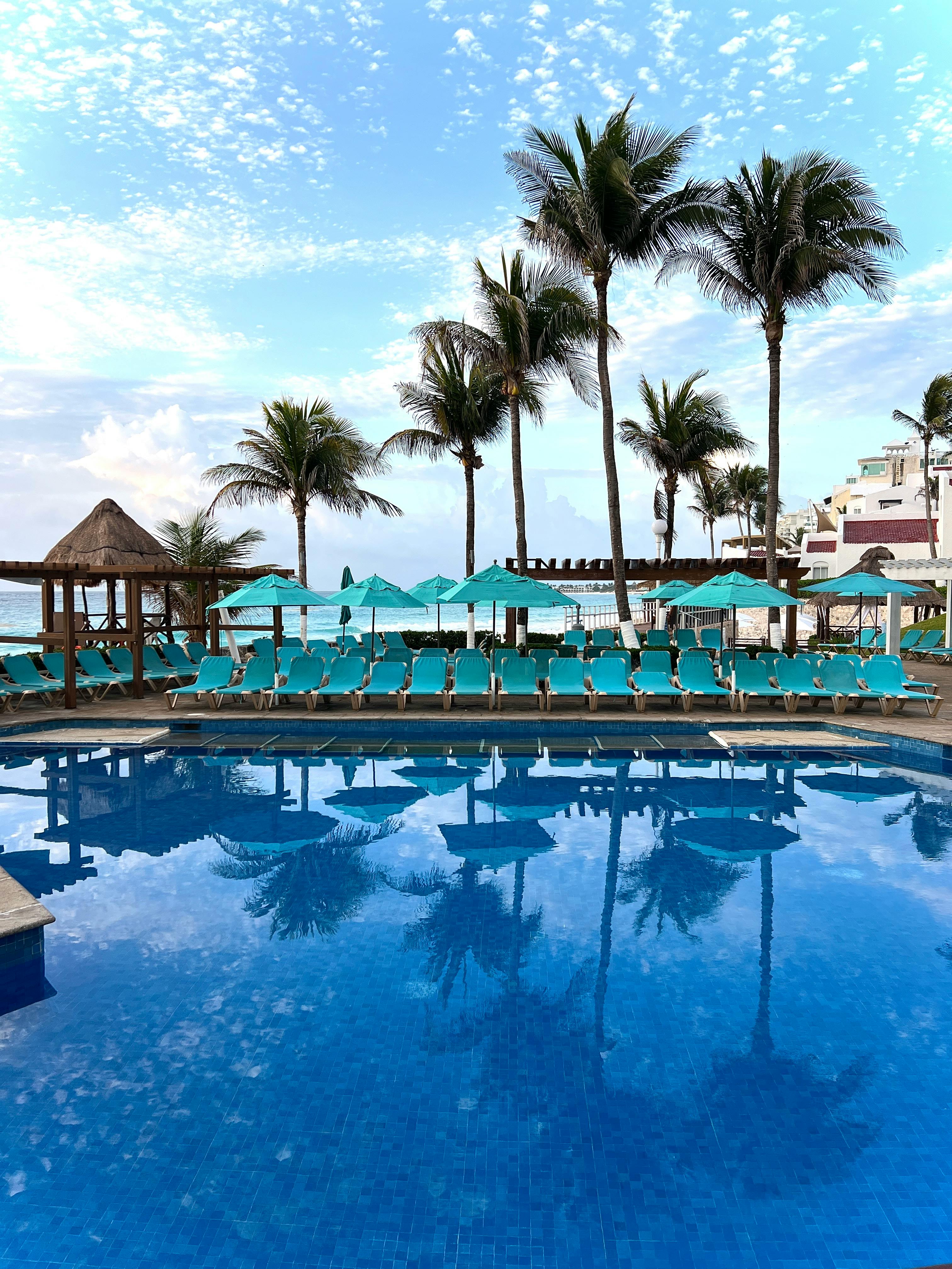 Tropical Resort Pool with Palm Trees and Umbrellas · Free Stock Photo