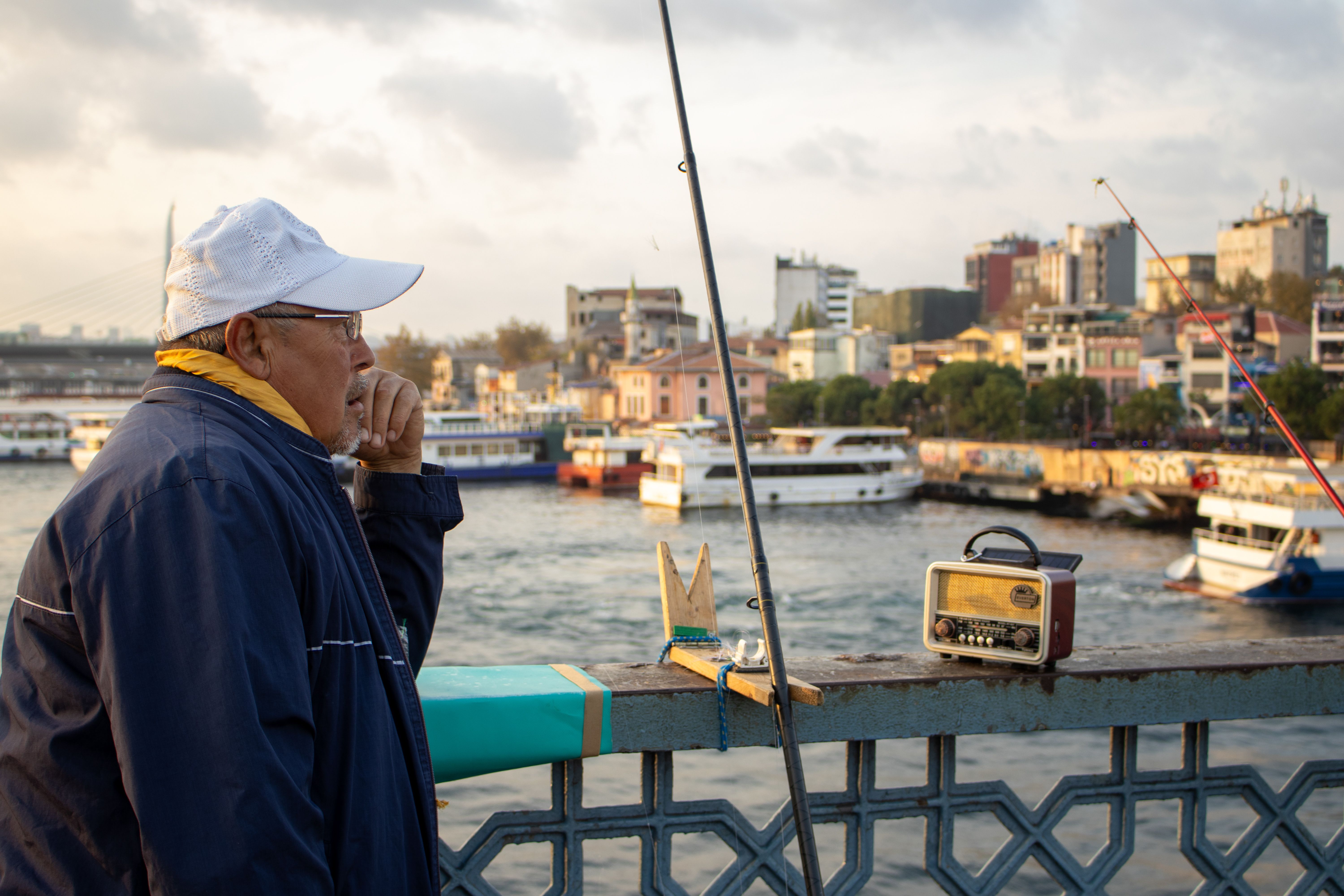 Elderly Man Fishing on Busy City Waterfront · Free Stock Photo