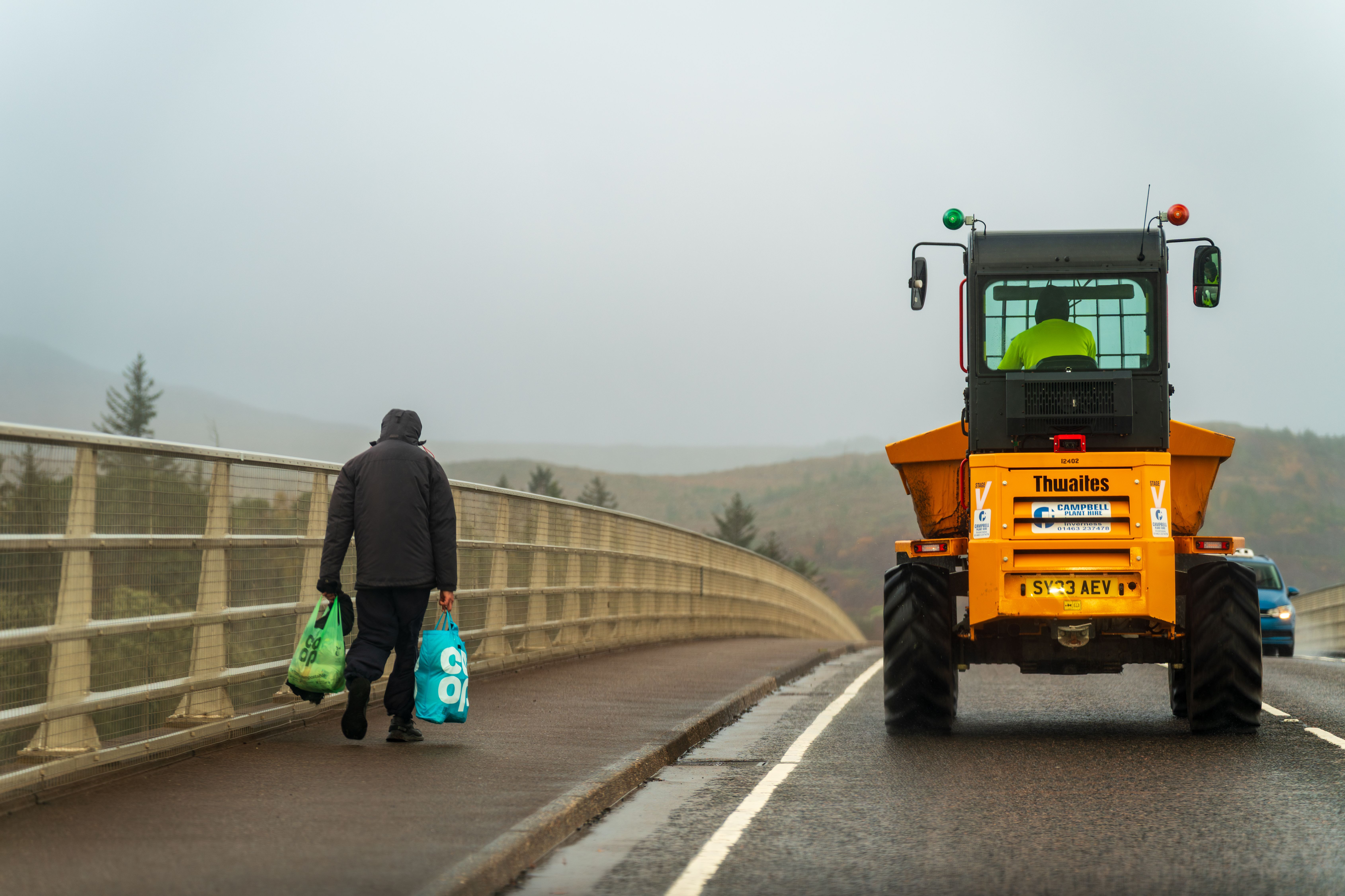 Man Walking on Bridge Beside Construction Vehicle · Free Stock Photo