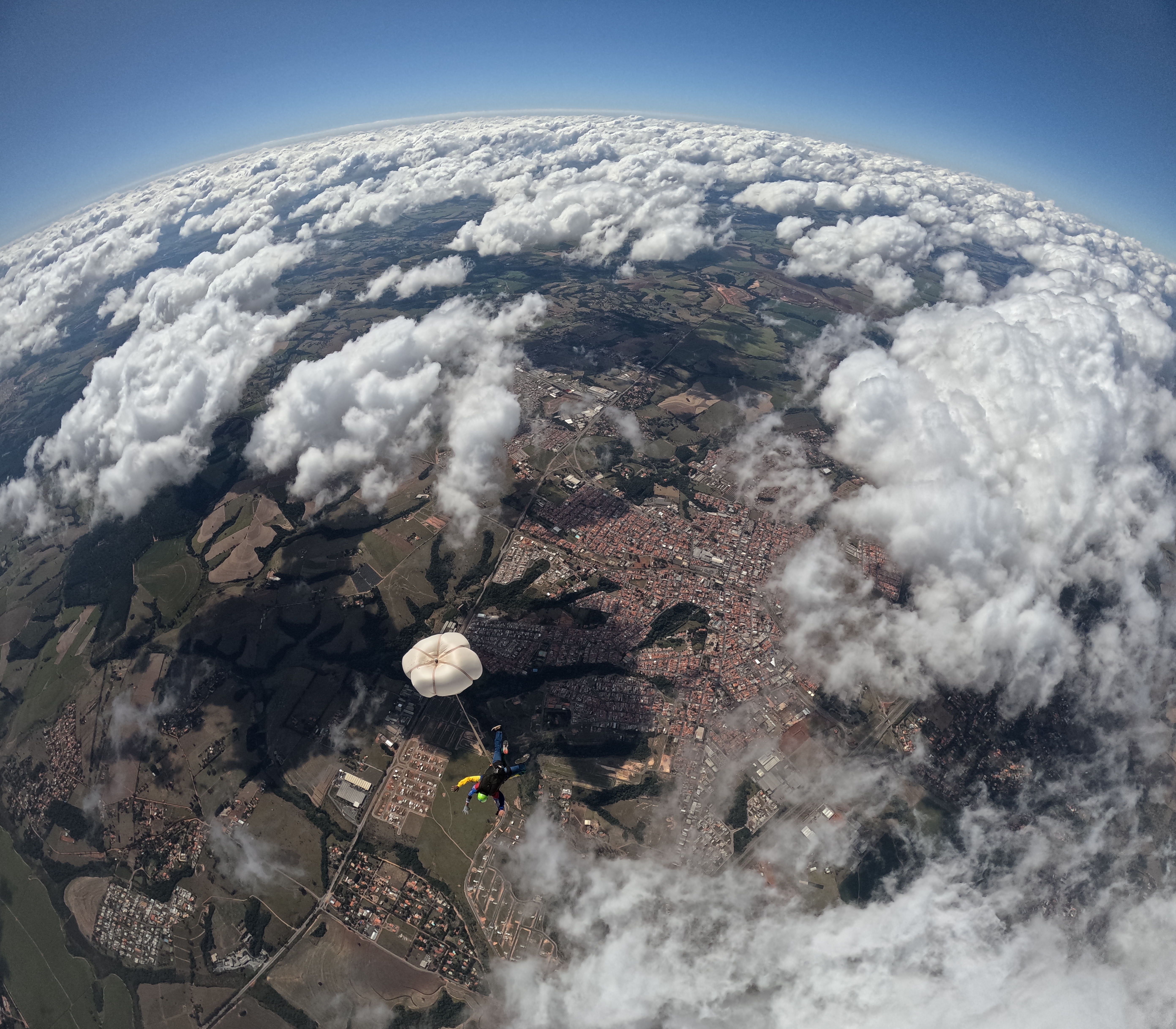 Aerial View of Skydiver with Parachute Over Cityscape · Free Stock Photo