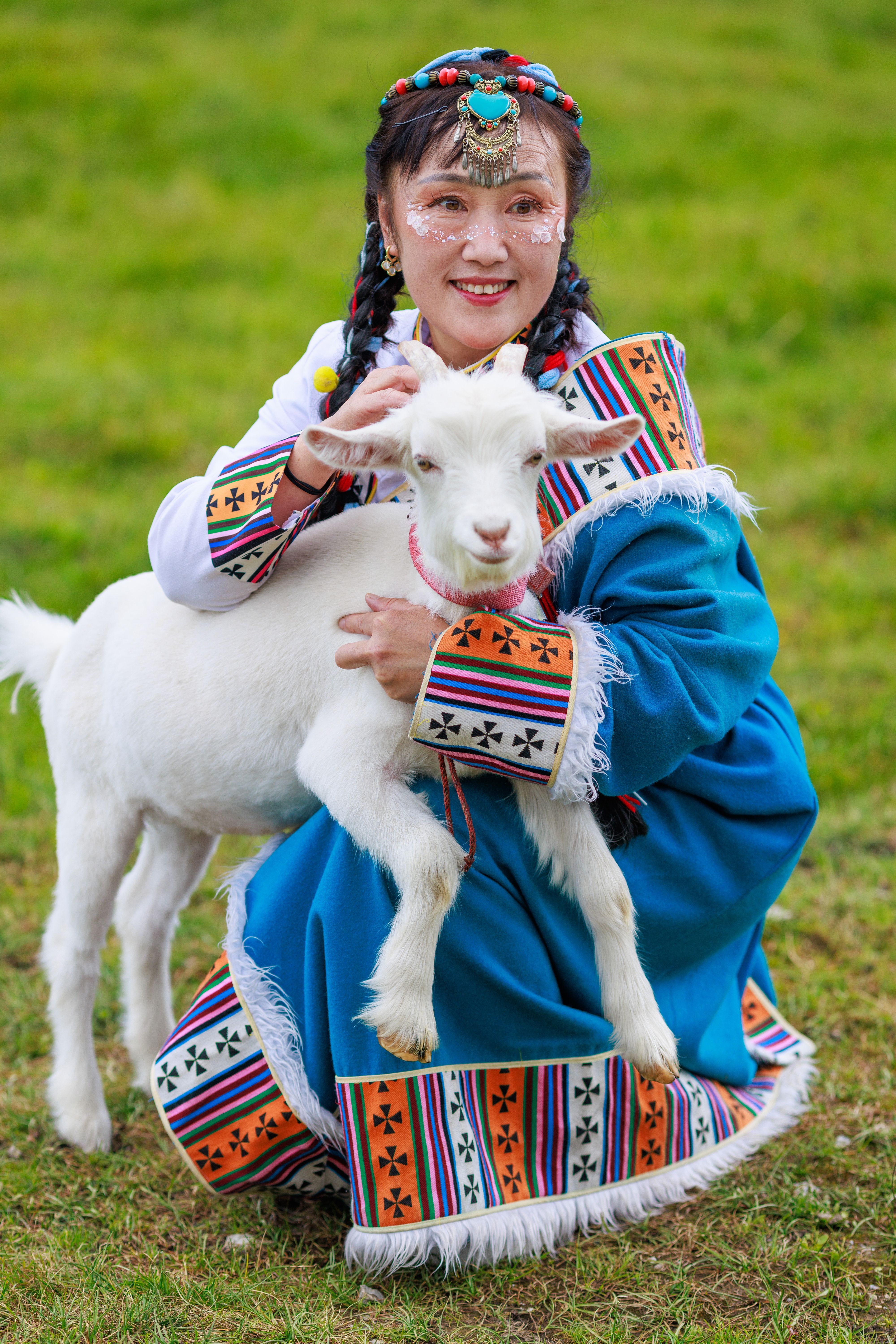 Woman in Traditional Dress Holding Goat Outdoors · Free Stock Photo