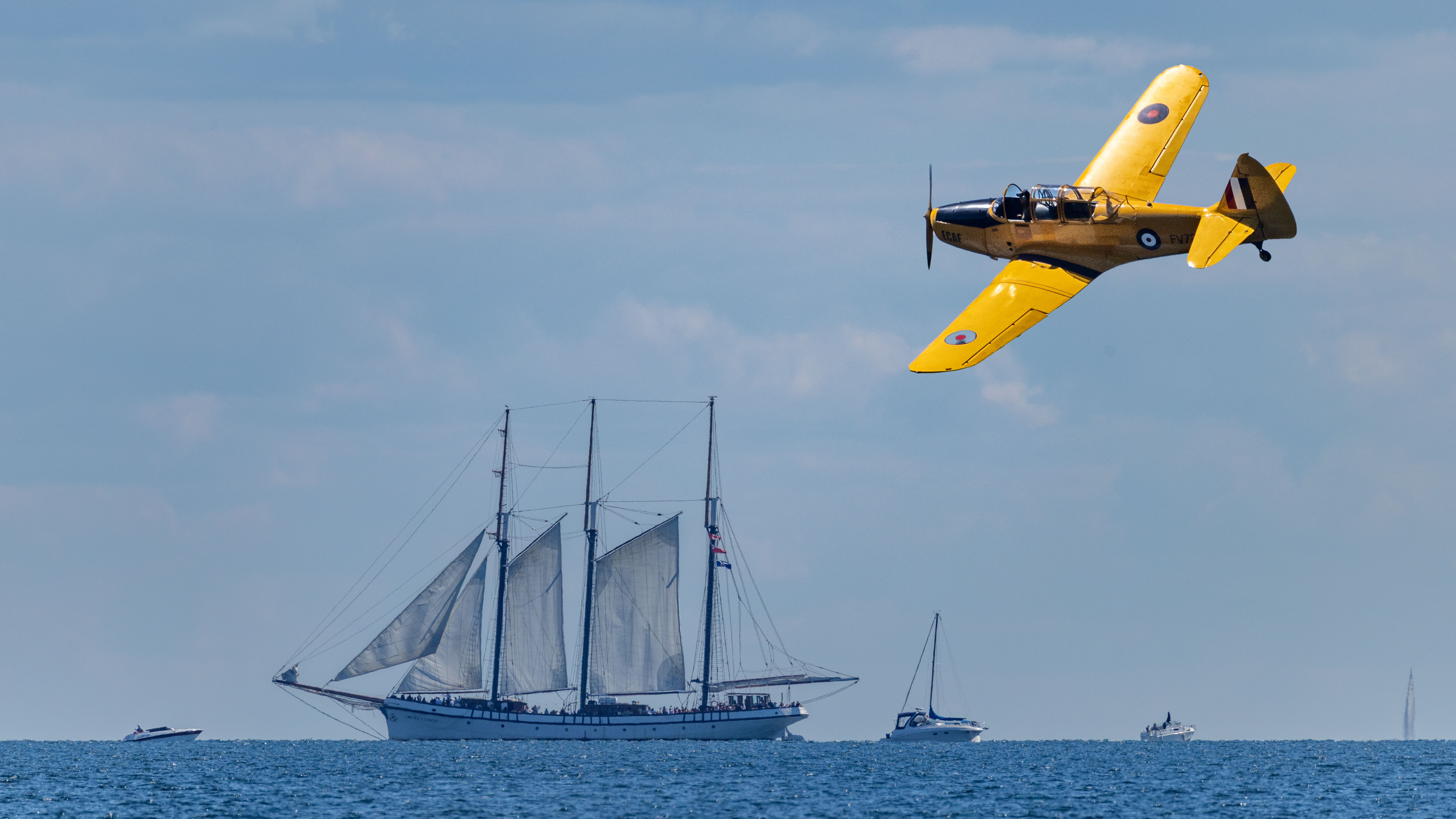 Vibrant Yellow Plane Performing Aerial Stunt at Sea · Free Stock Photo