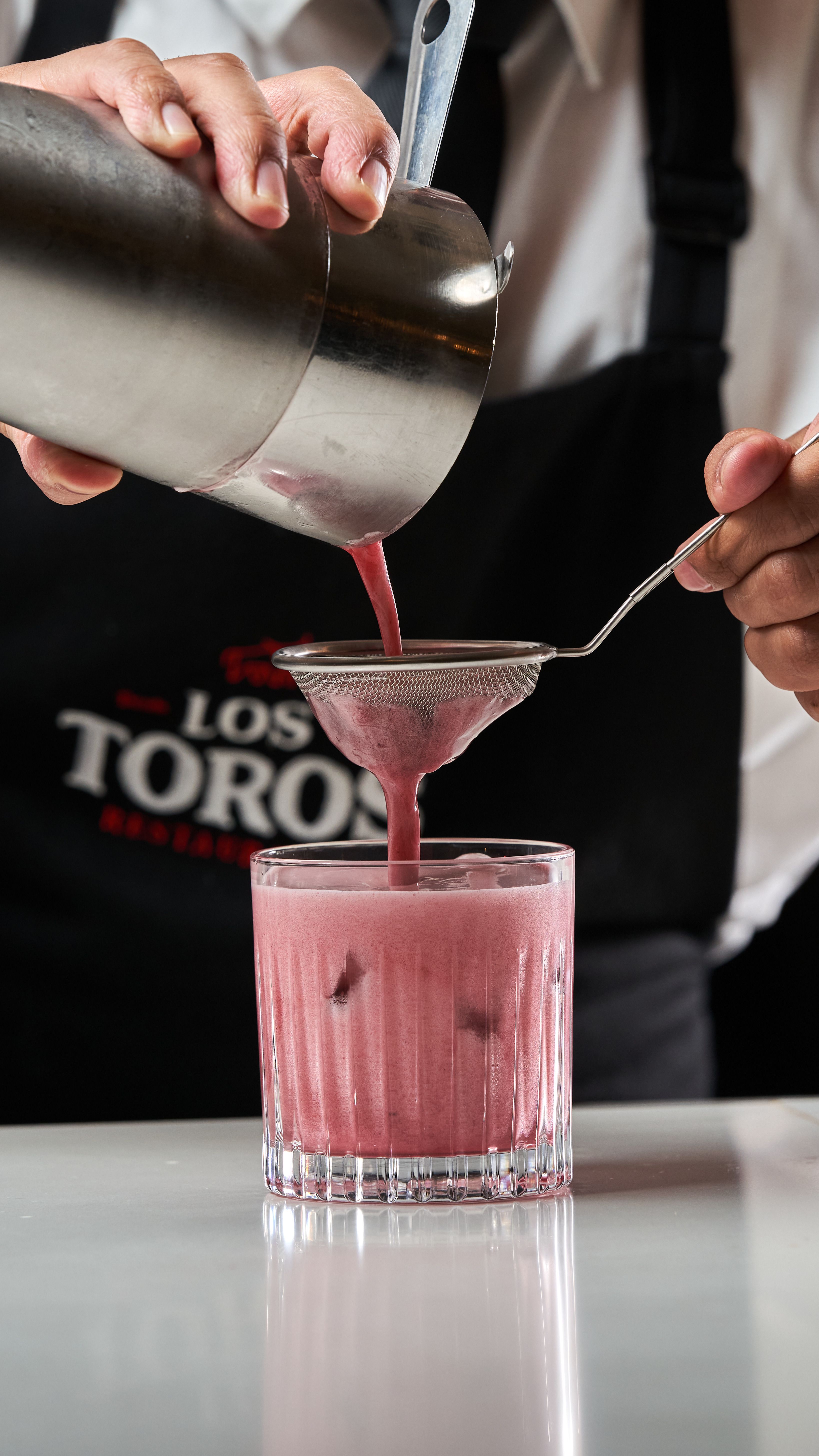 Bartender Straining Pink Cocktail into Glass · Free Stock Photo