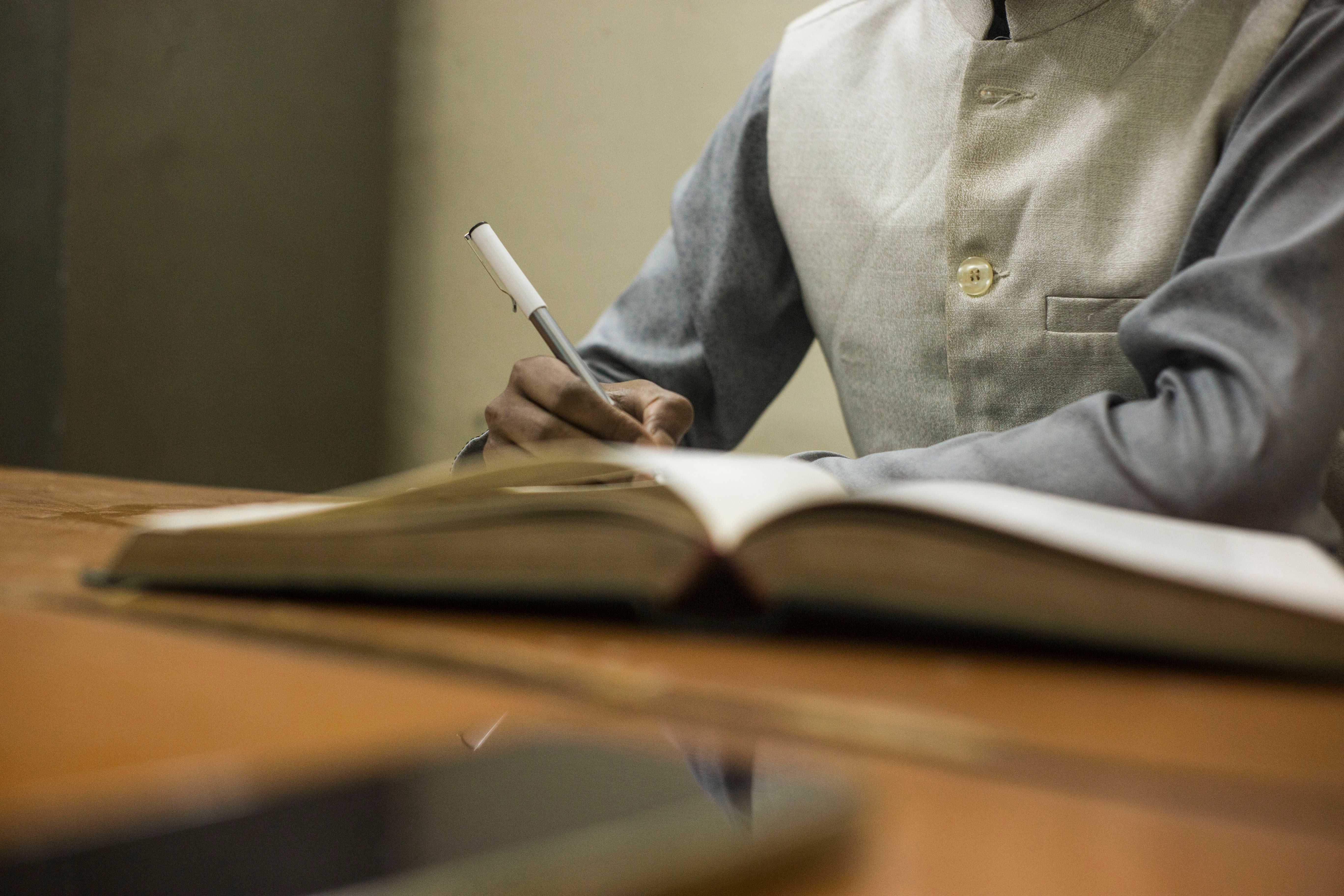 Thoughtful man writing in notebook and studying in home office · Free ...