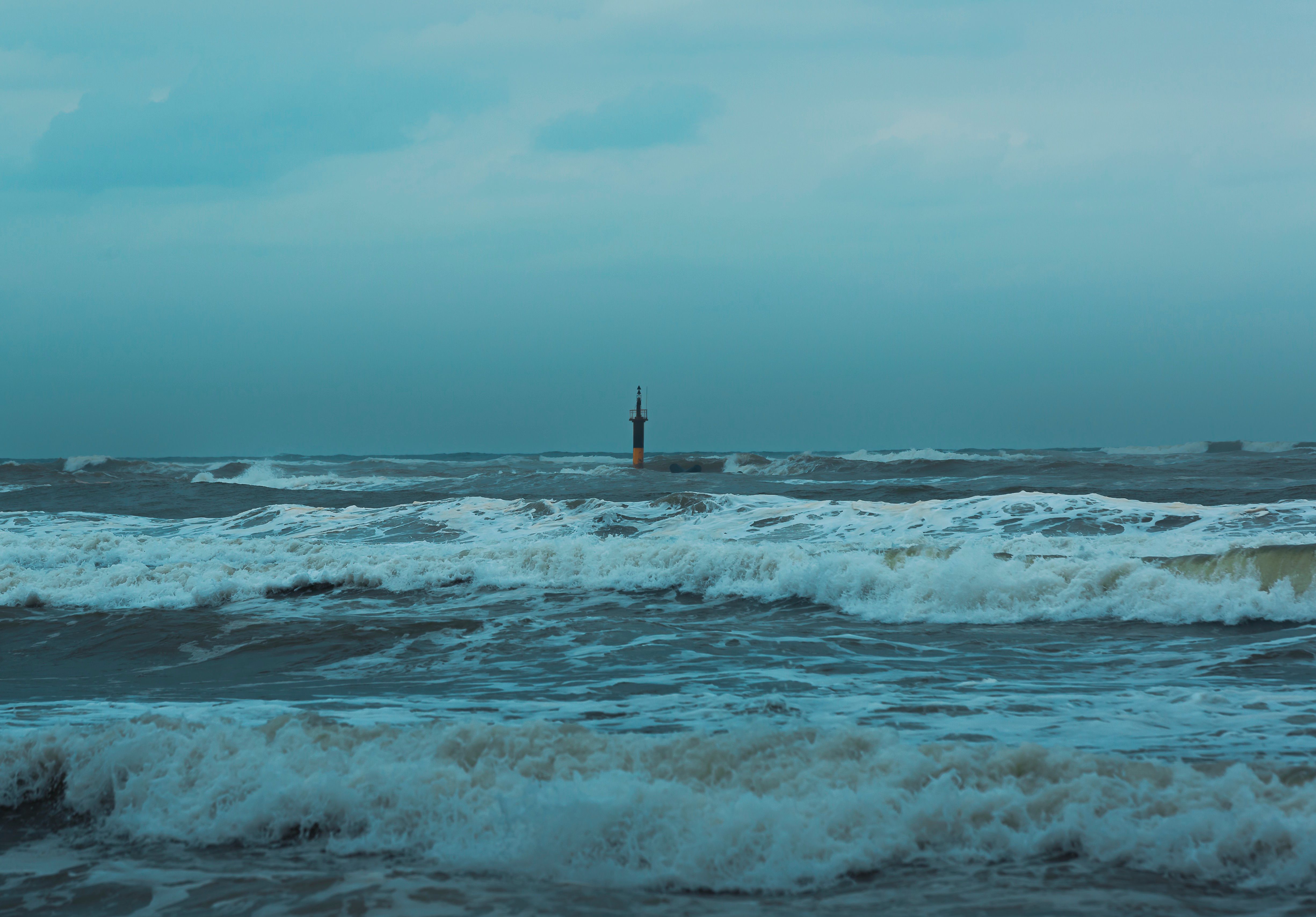 Dramatic Ocean Waves with Distant Lighthouse View · Free Stock Photo