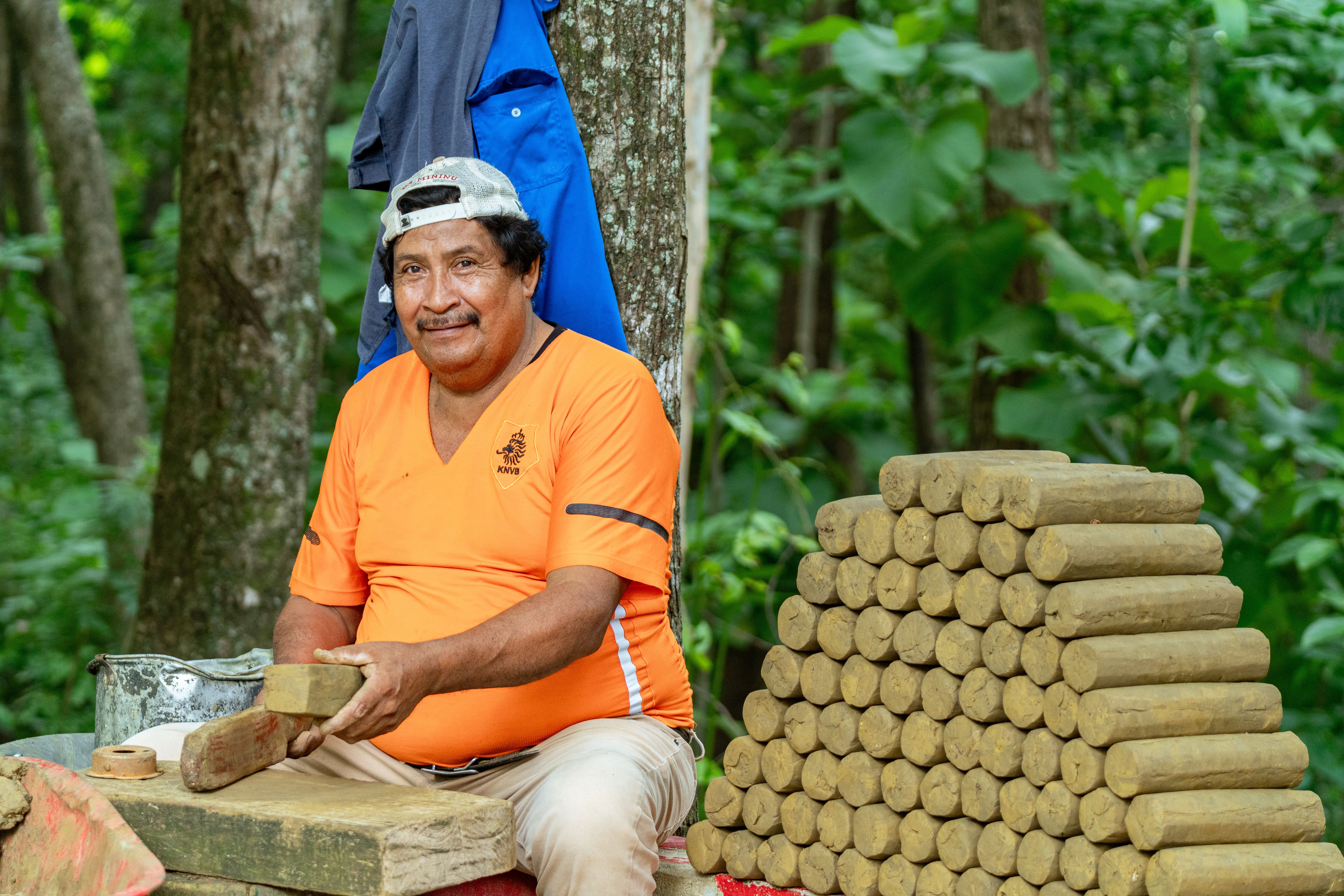 Man Making Adobe Bricks in Forest Setting · Free Stock Photo