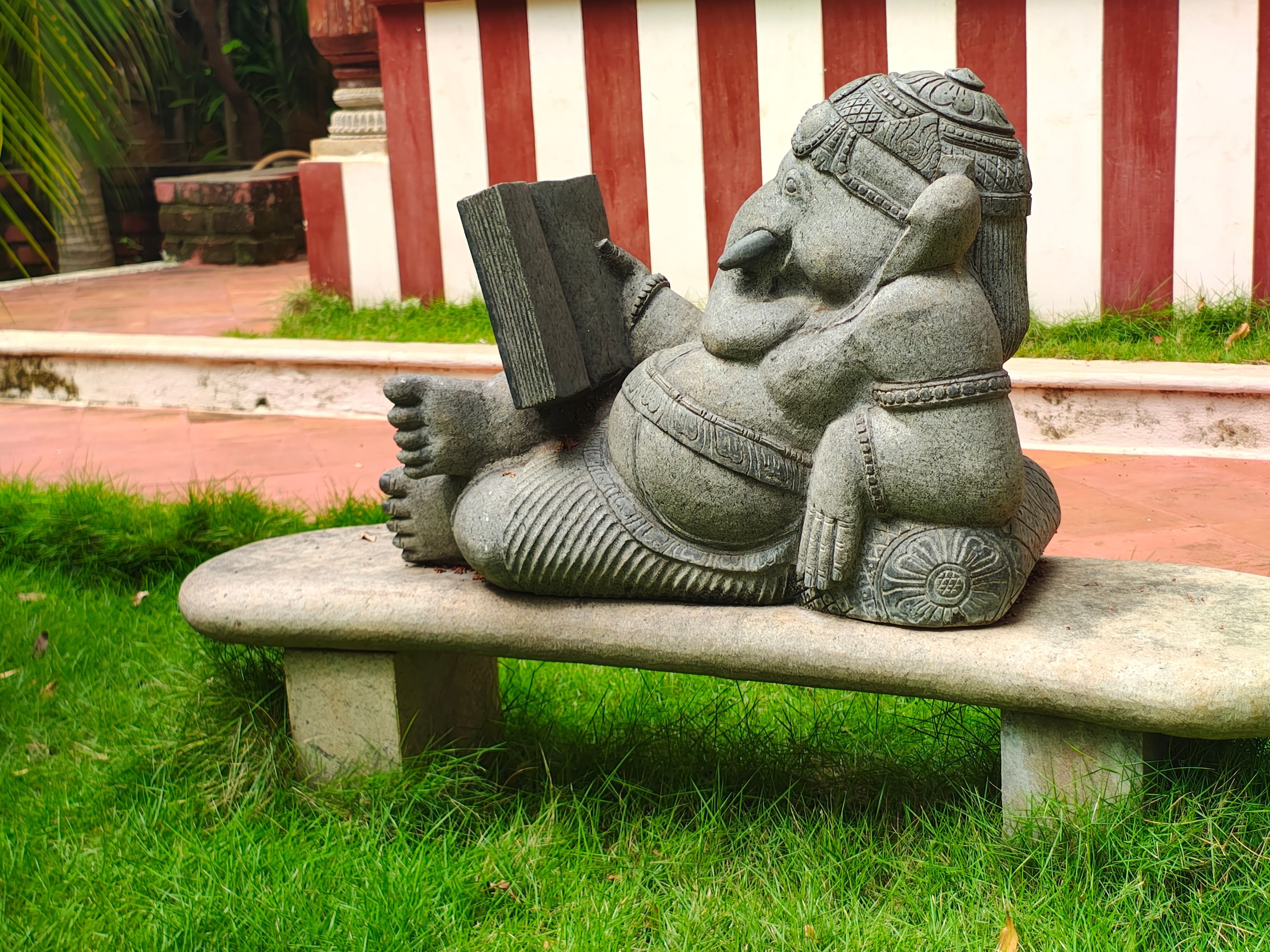 Relaxed Ganesha Statue Reading on Stone Bench · Free Stock Photo