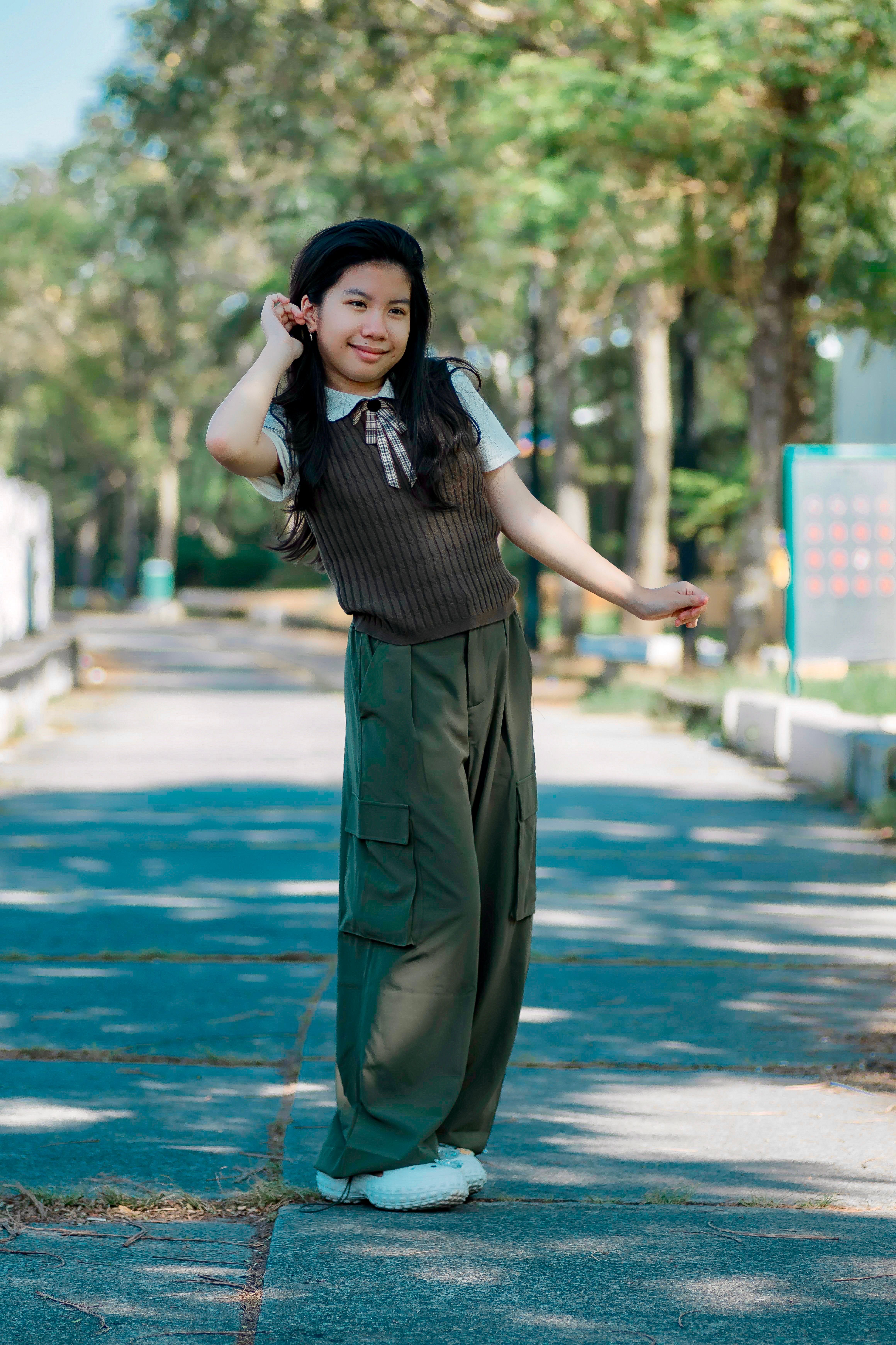 Cheerful Girl Posing Outdoors in Sunlit Park · Free Stock Photo