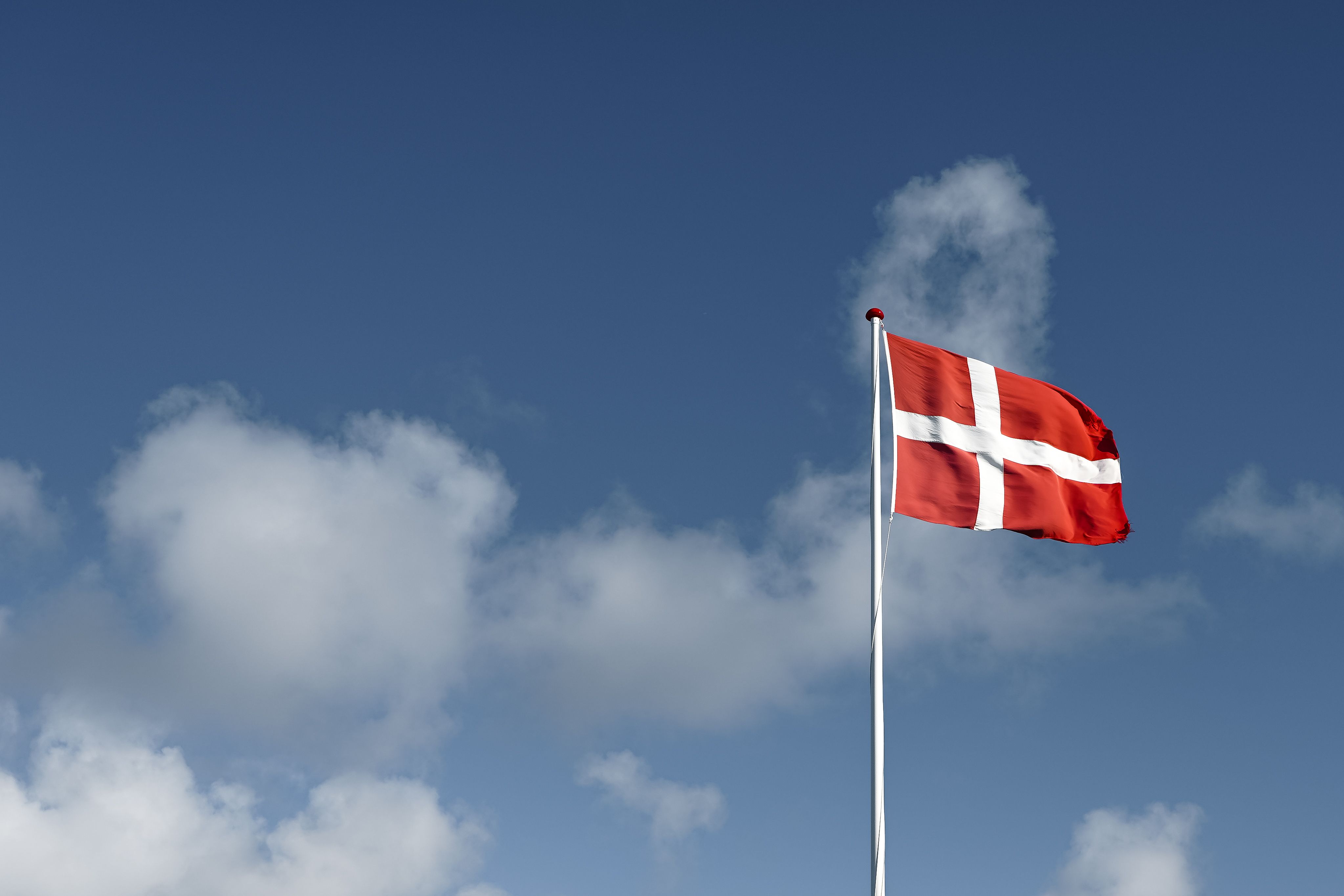 Danish Flag Waving Against a Blue Sky in Hvide Sande · Free Stock Photo