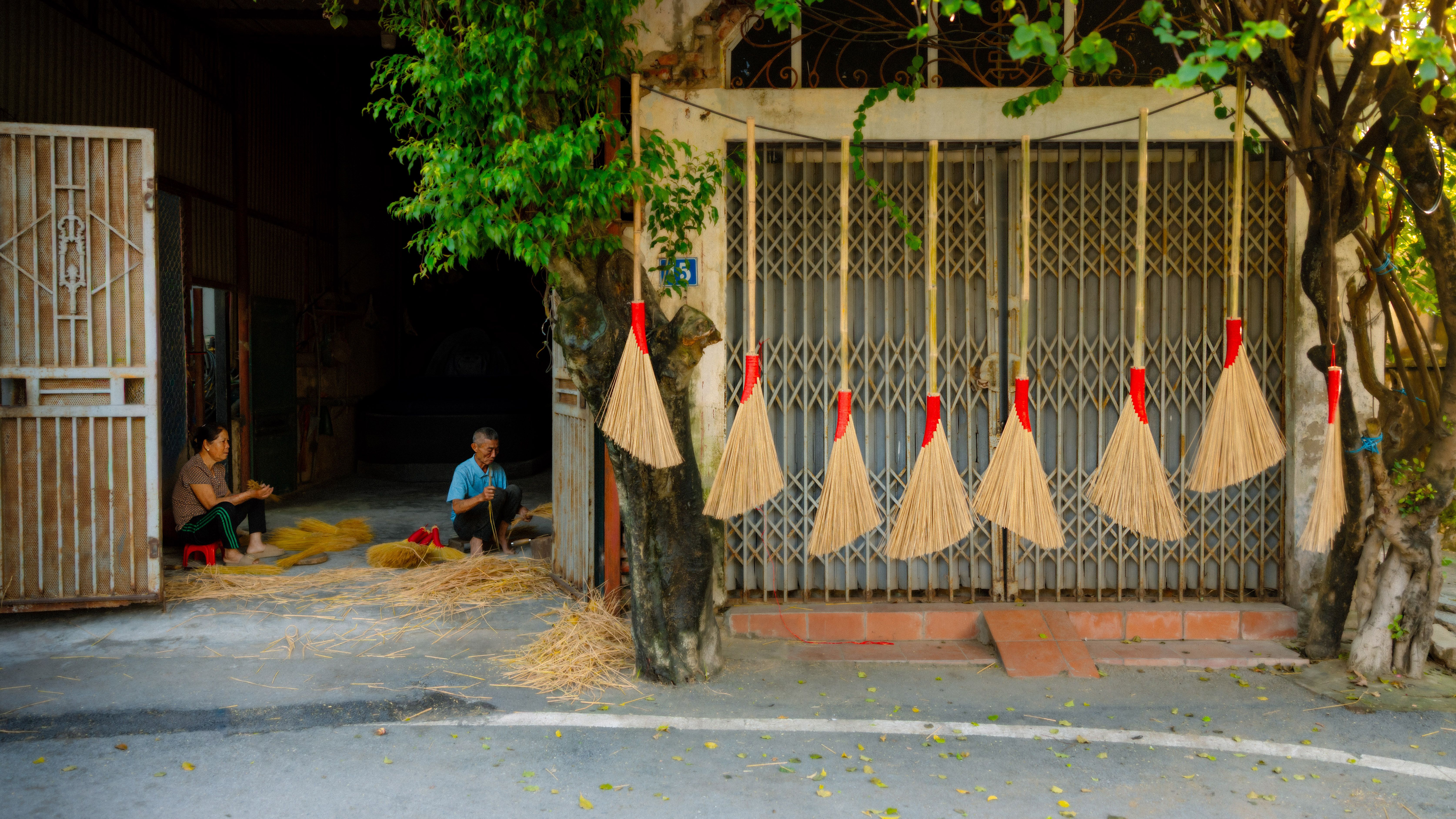 Traditional broom making outside a rural workshop · Free Stock Photo