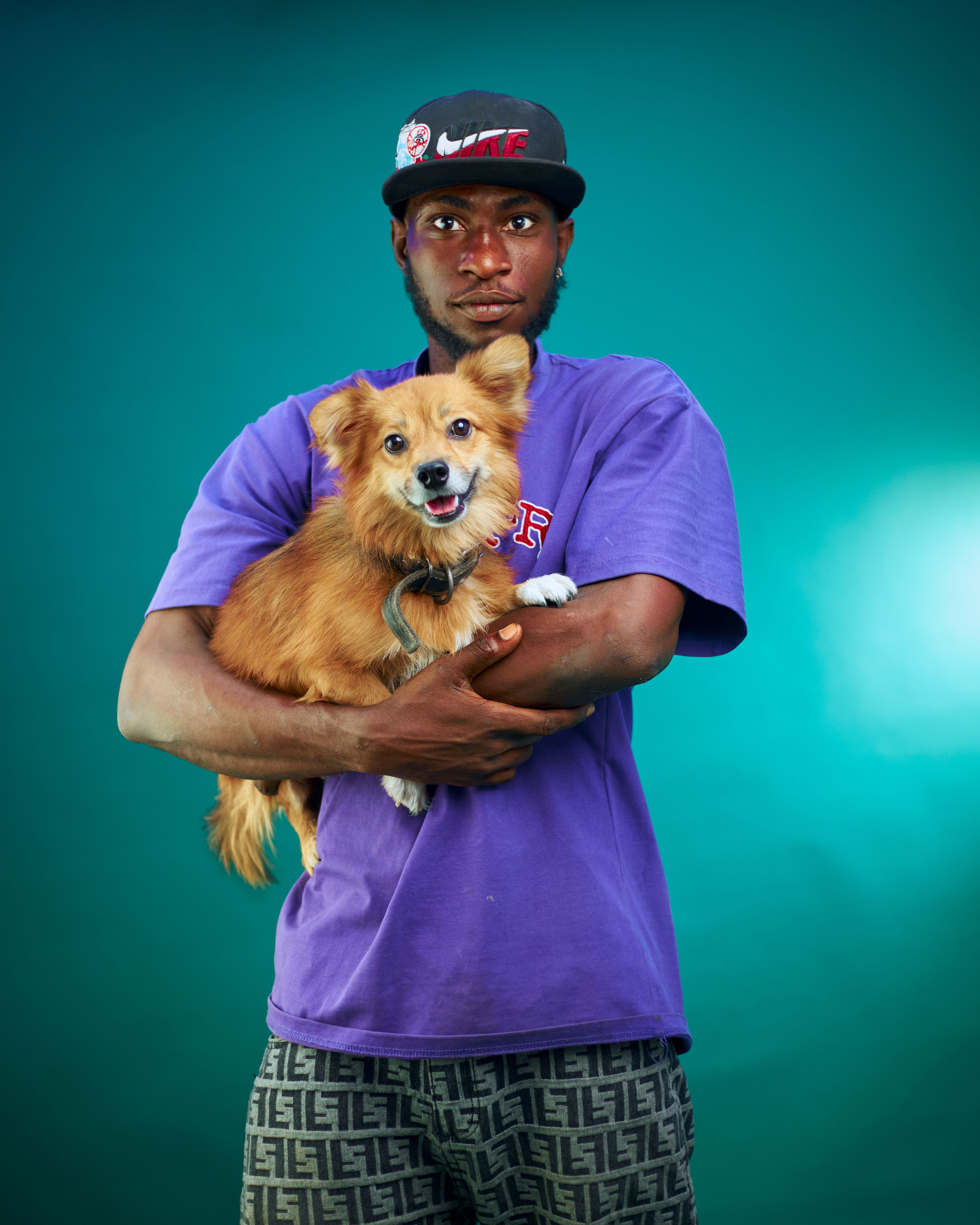 Portrait of Man Holding Fluffy Dog on Teal Background · Free Stock Photo
