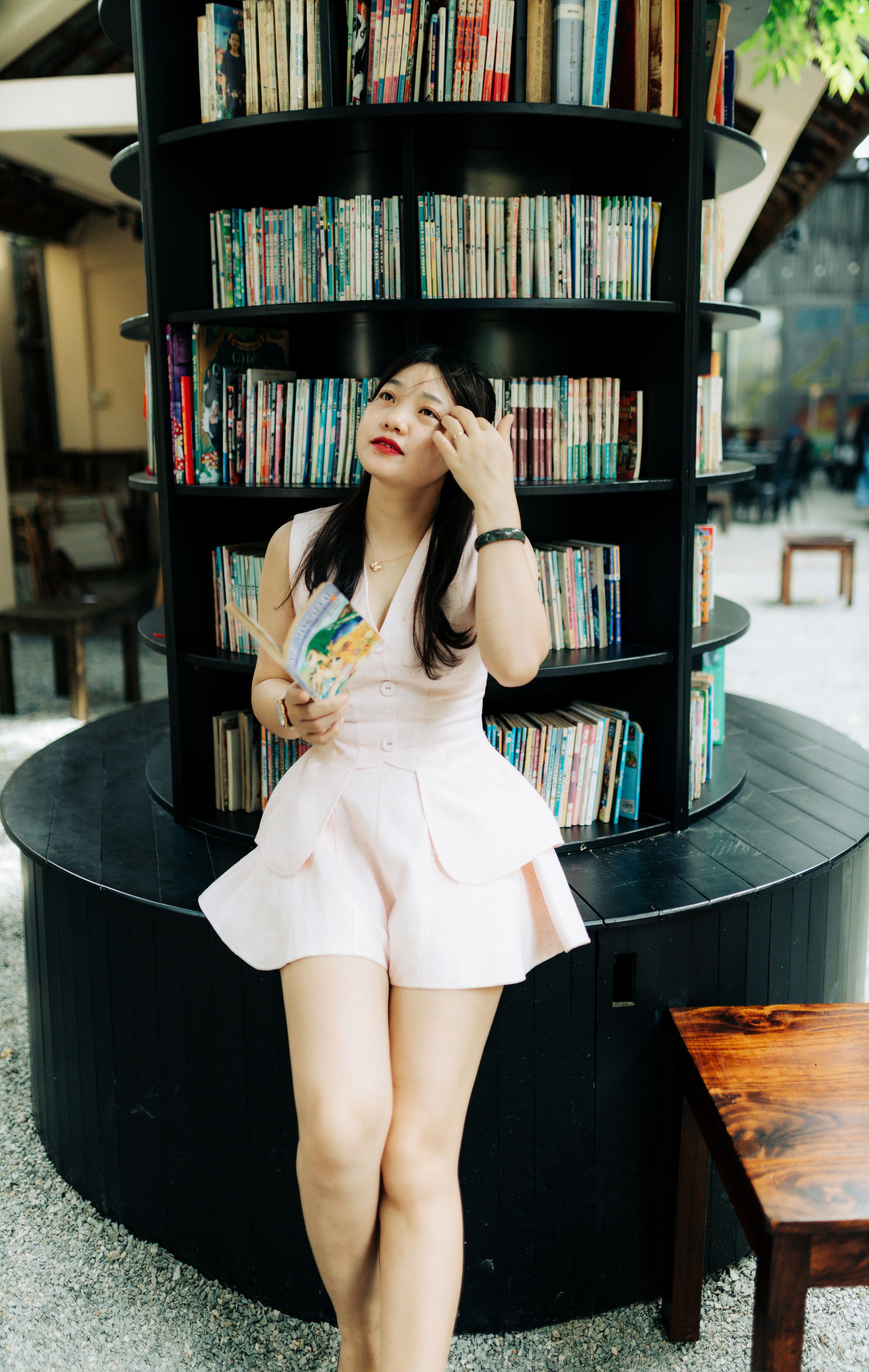 Young Woman in Library Leaning on Bookcase · Free Stock Photo