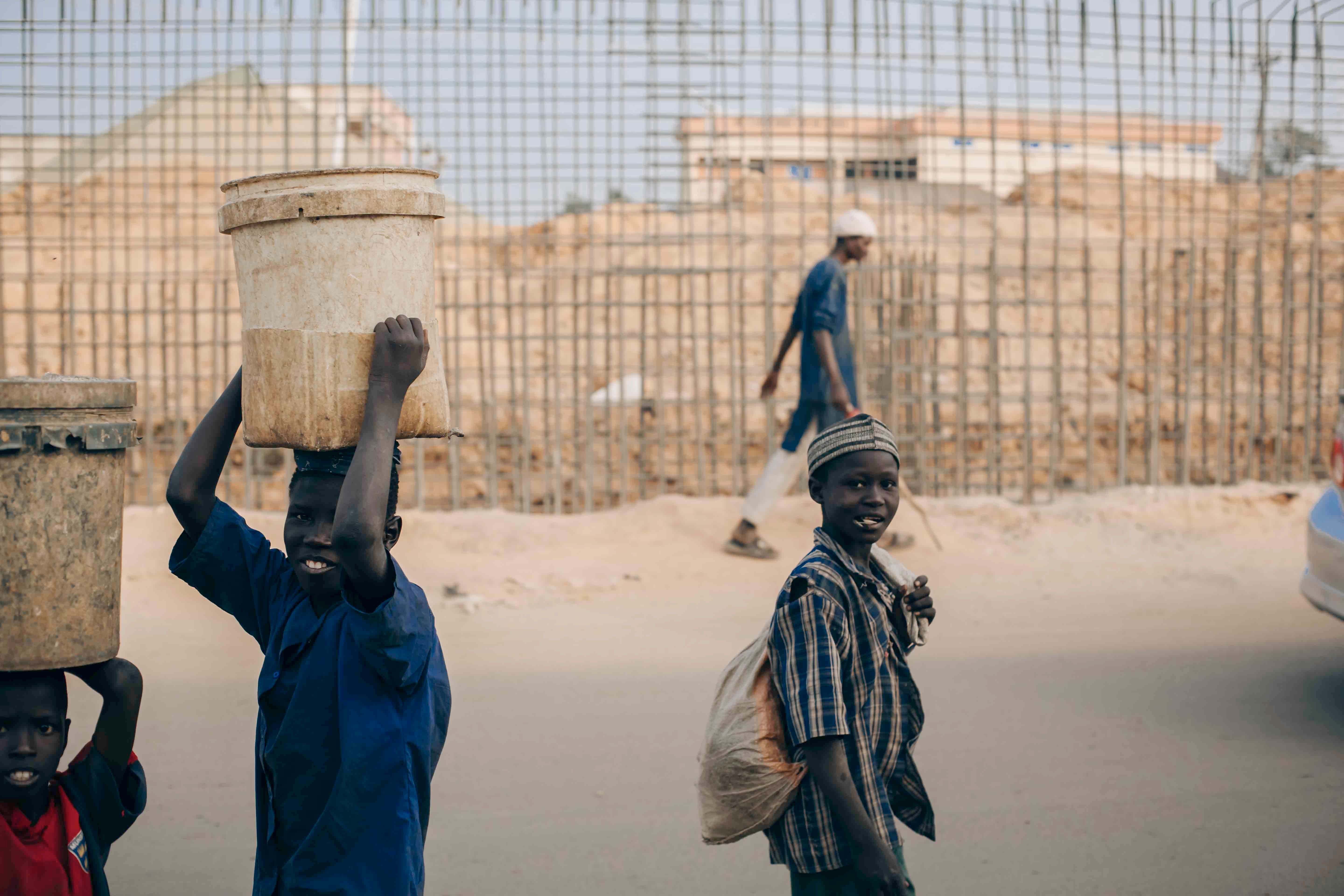 Young boys carrying buckets in a bustling street · Free Stock Photo