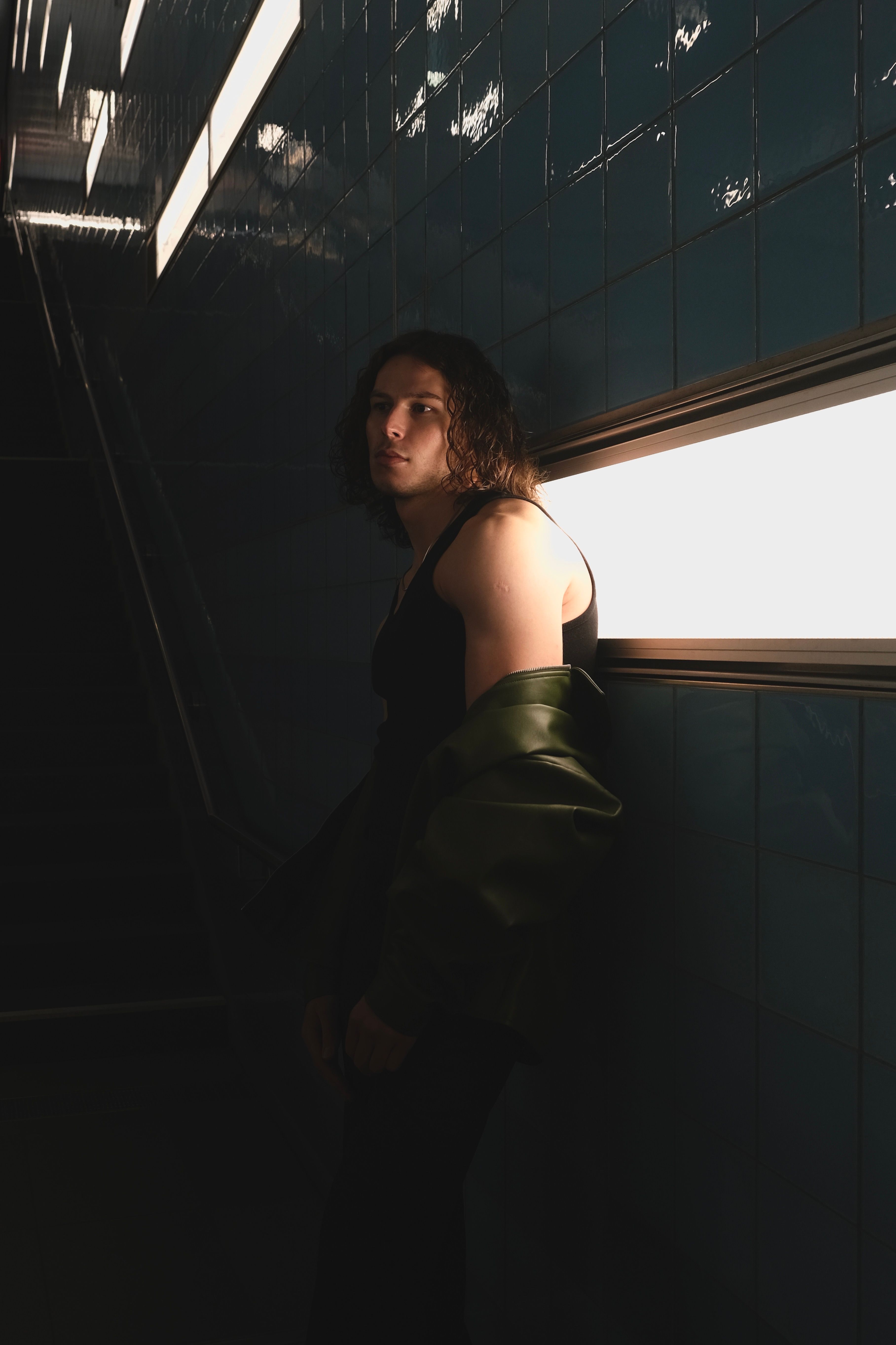 Moody Portrait in Dimly Lit Urban Stairwell · Free Stock Photo