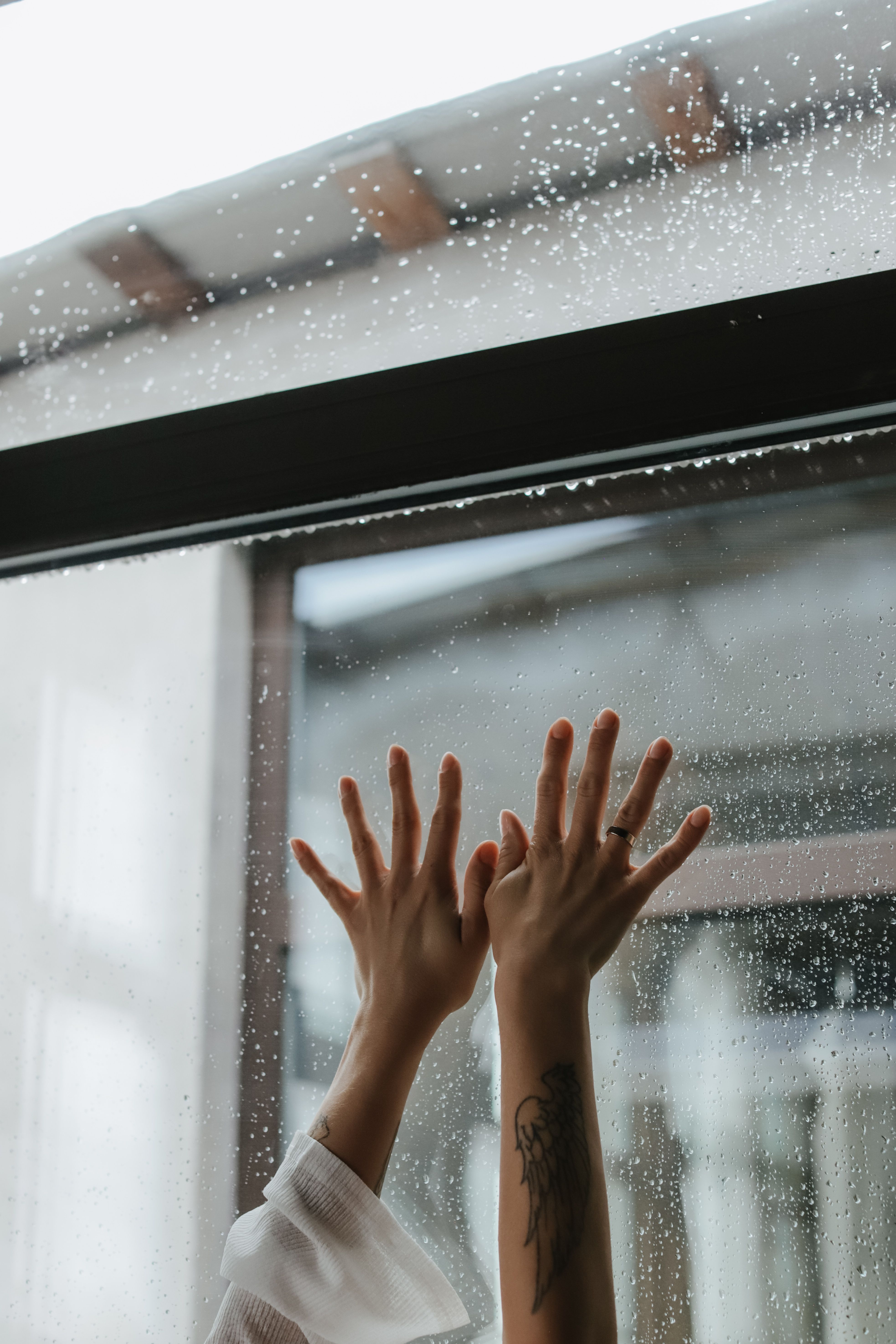 Hands reaching up against rainy window · Free Stock Photo